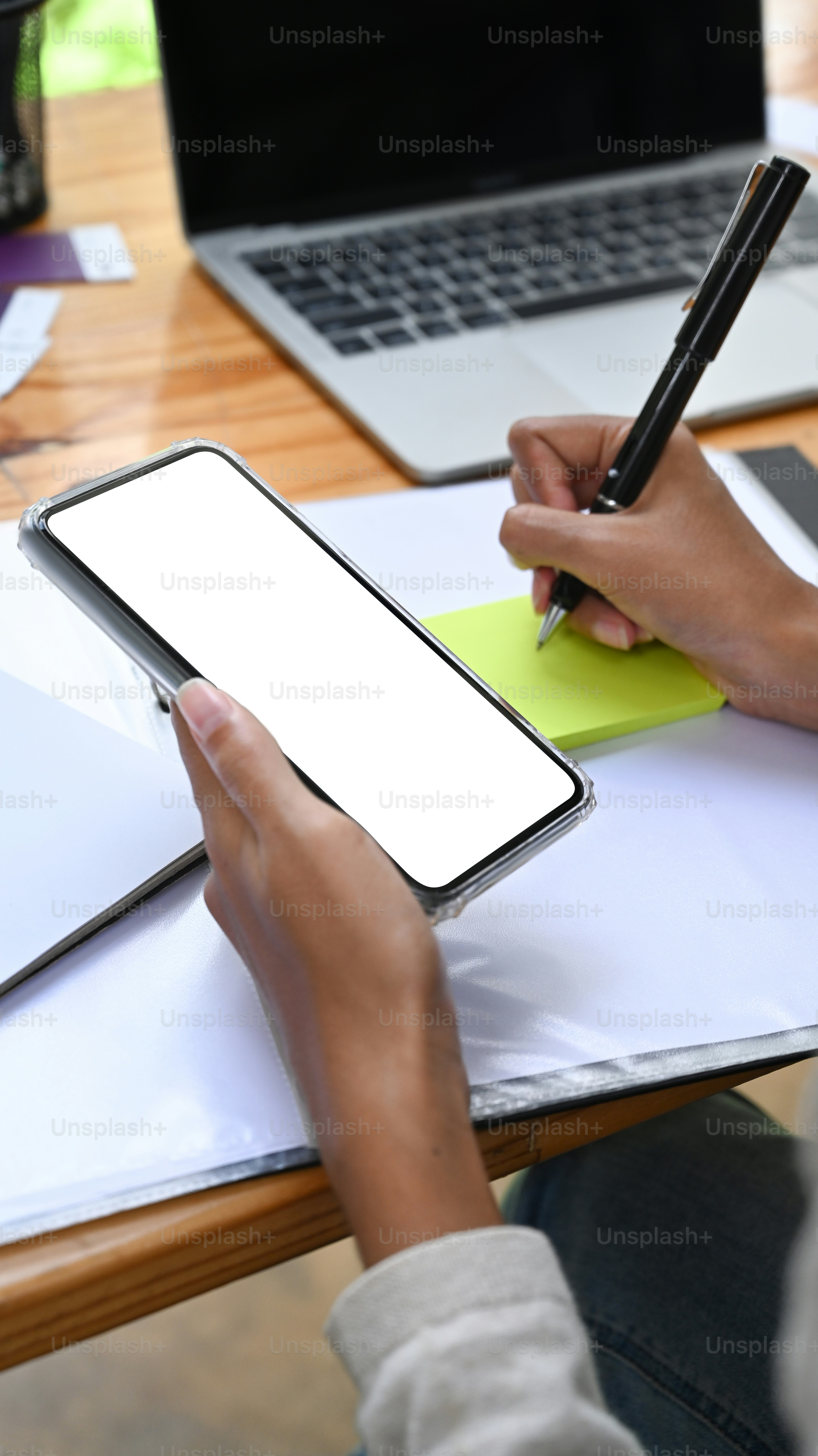 Businesswoman making note on sticky note and using smart phone. photo ...