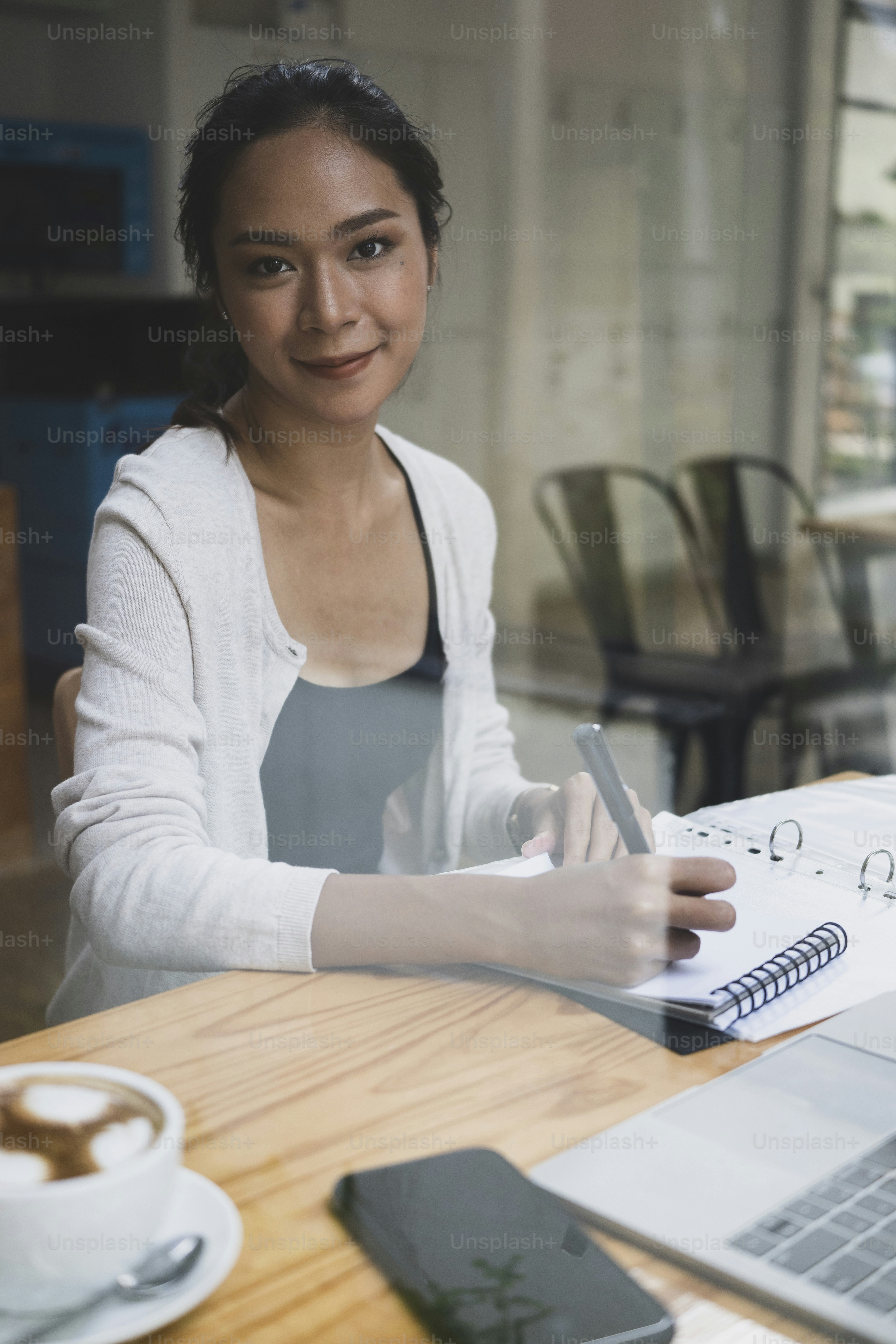 Attractive businesswoman sitting at her workplace and smiling to camera ...