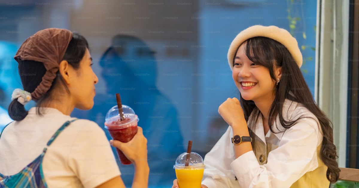 젊은 아름다운 아시아 여자 친구들은 카페 창가에 앉아 과일 주스를 마시고 행복과 함께 이야기합니다 매력적인 여성 우정은