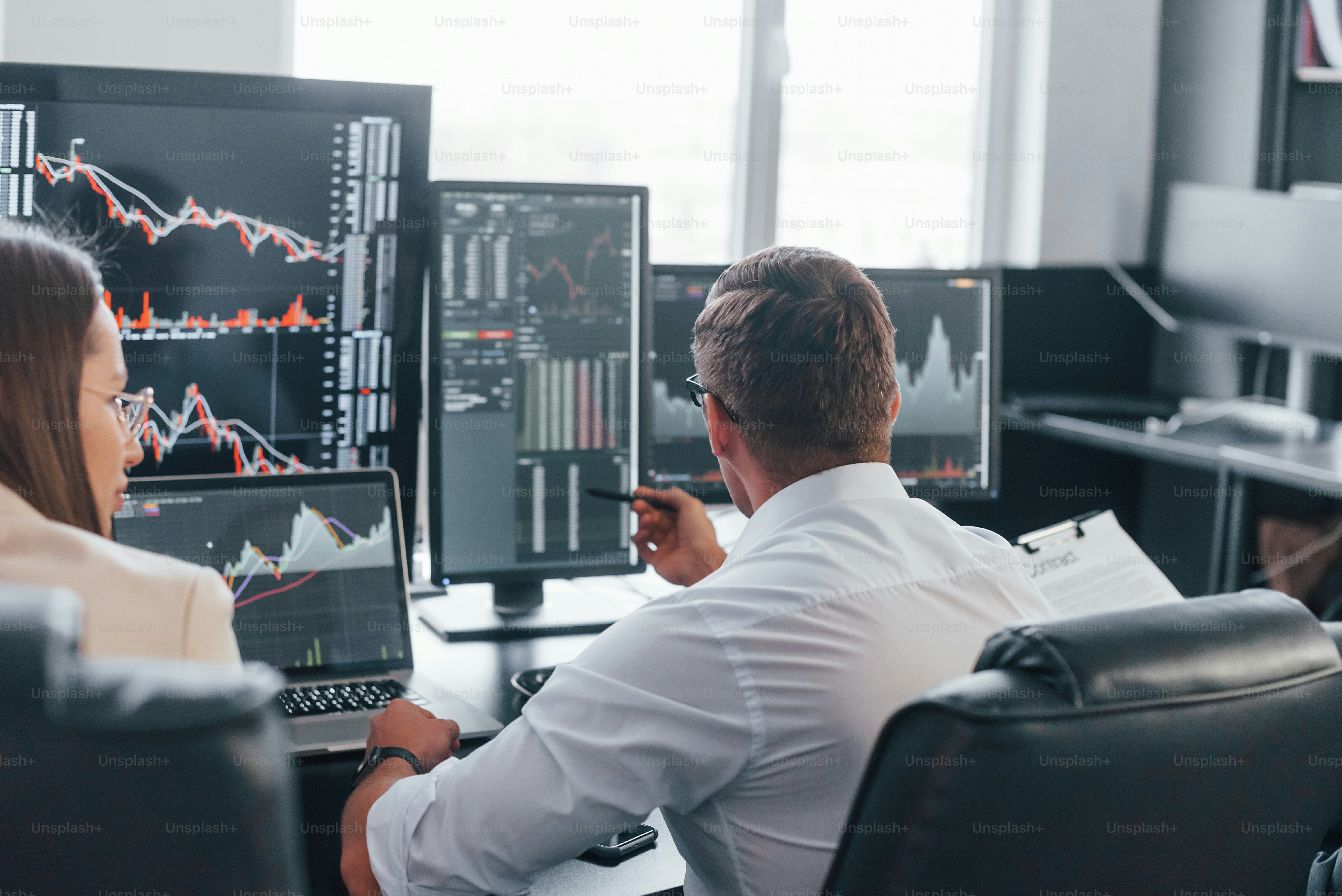 Sitting by the table. Team of stockbrokers works in modern office with ...