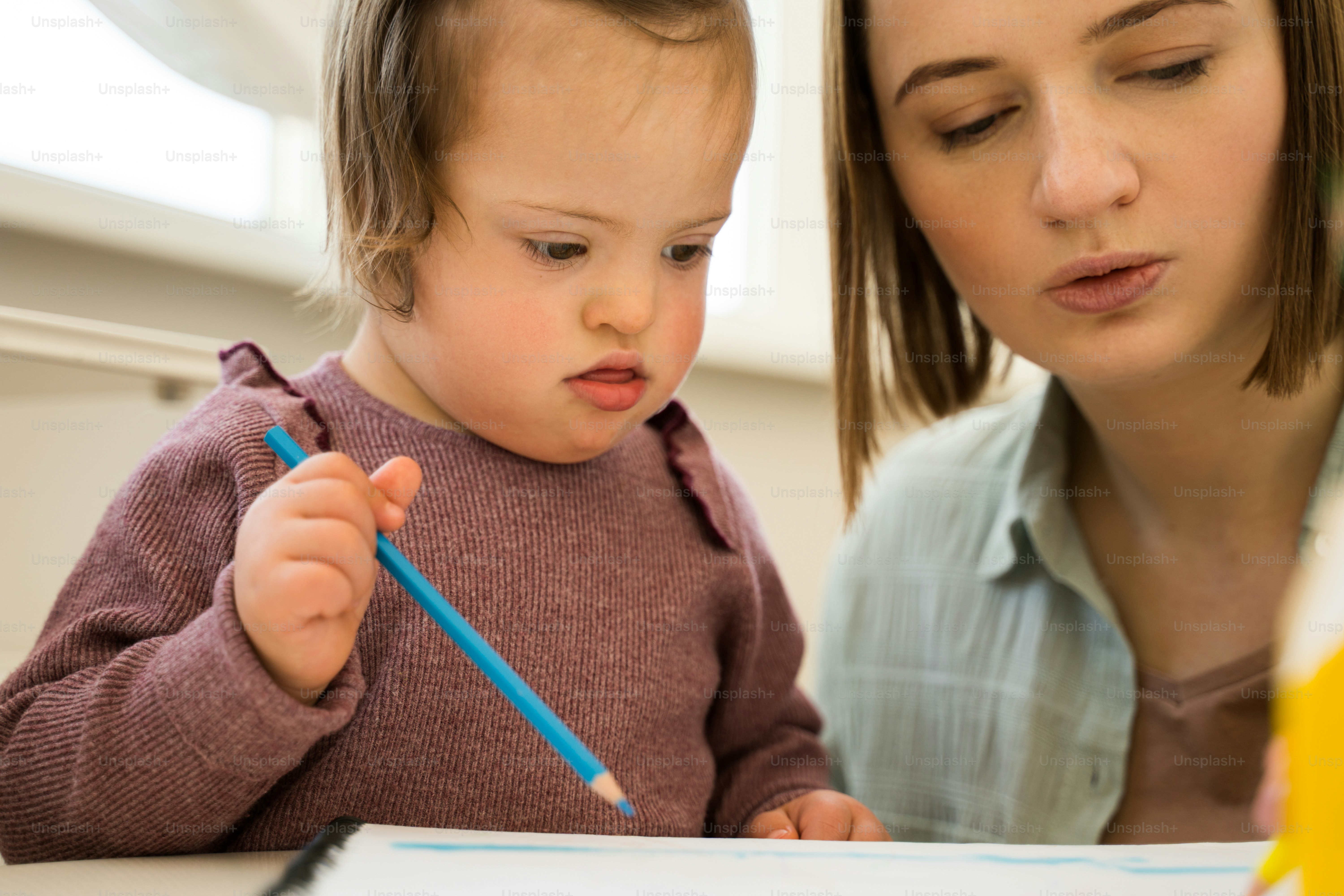 Hmm. Petite fille trisomique dessinant assidûment près de sa mère ...