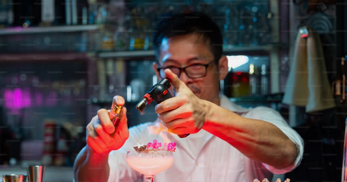자신감 아시아 여성은 바 카운터에 앉아 알코올 음료를 마시고 나이트 클럽에서 바텐더와 이야기합니다 남성 믹솔로지스트 바텐더가