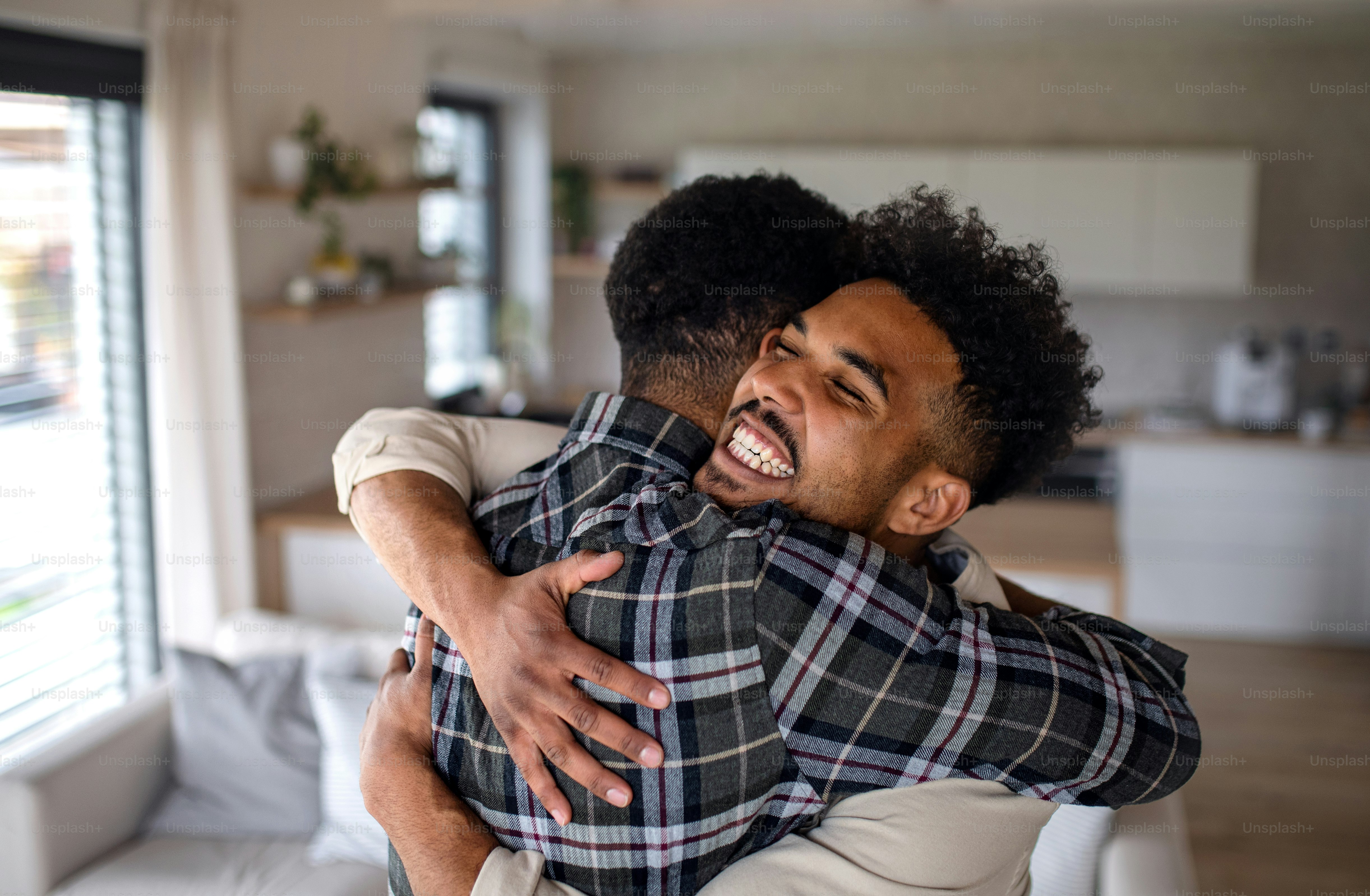 A young happy adult brothers in kitchen indoors at home, hugging. photo ...