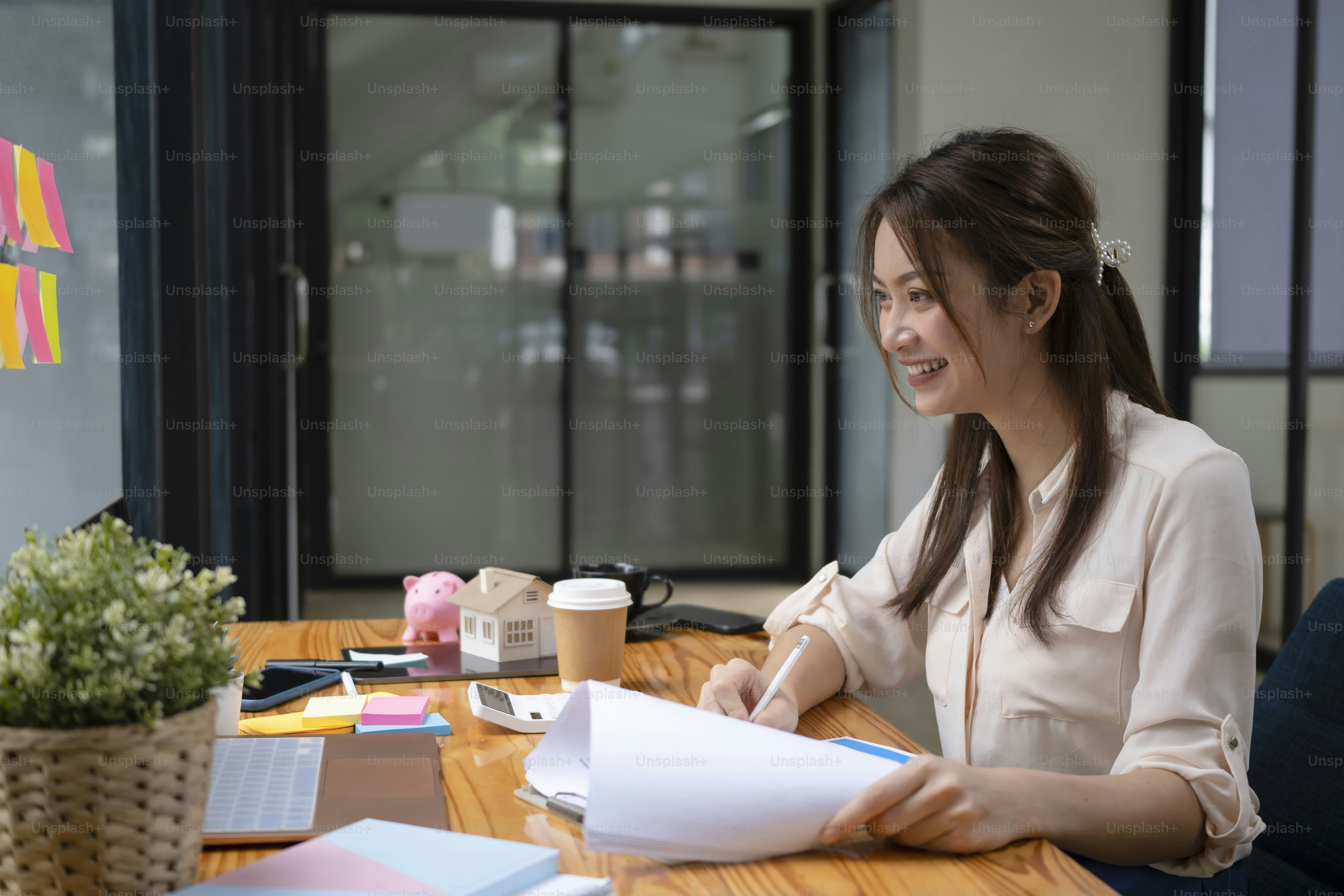 Smiling female office worker checking report at office desk. photo ...