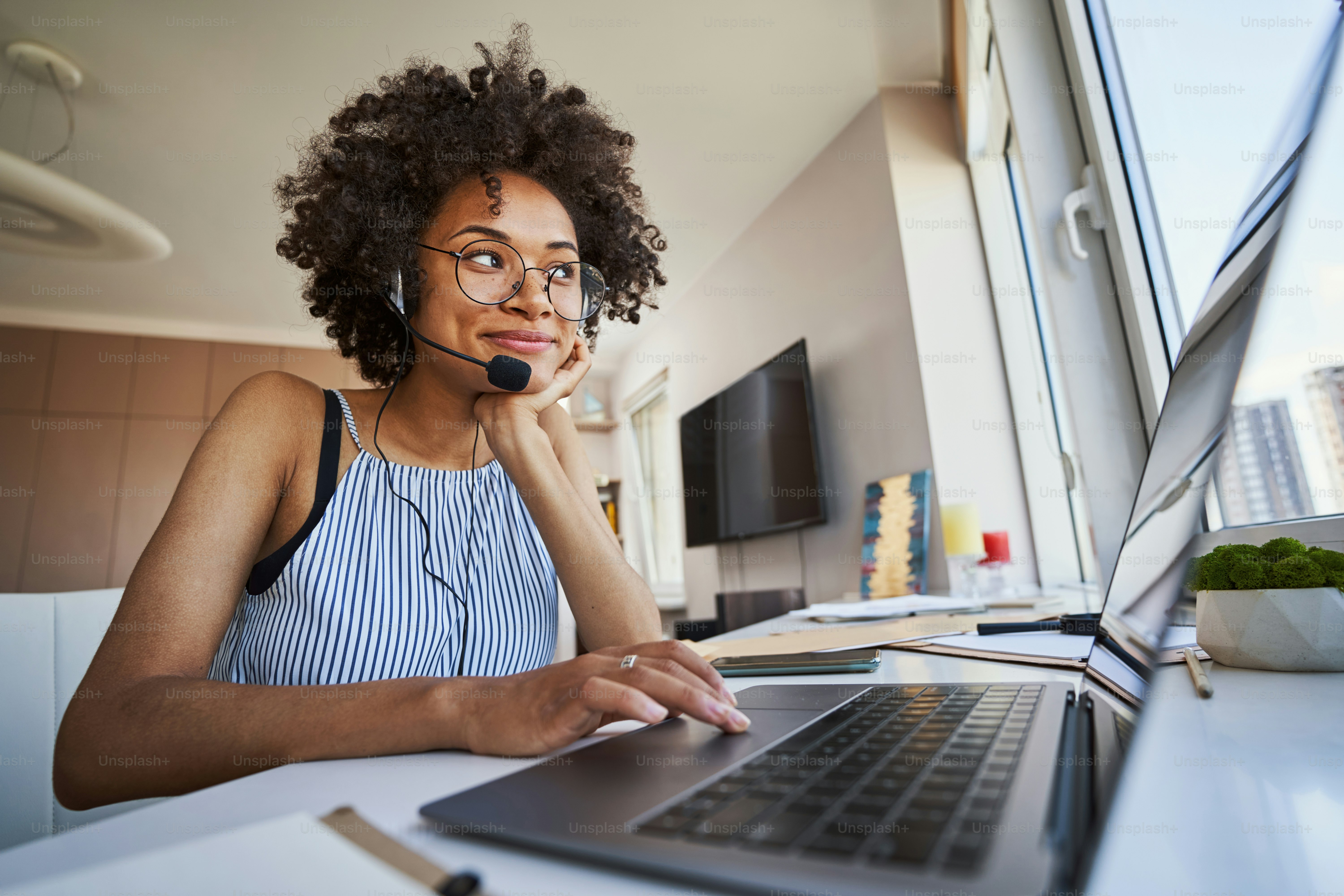 Portrait of a pleased female remote worker in the headset and ...