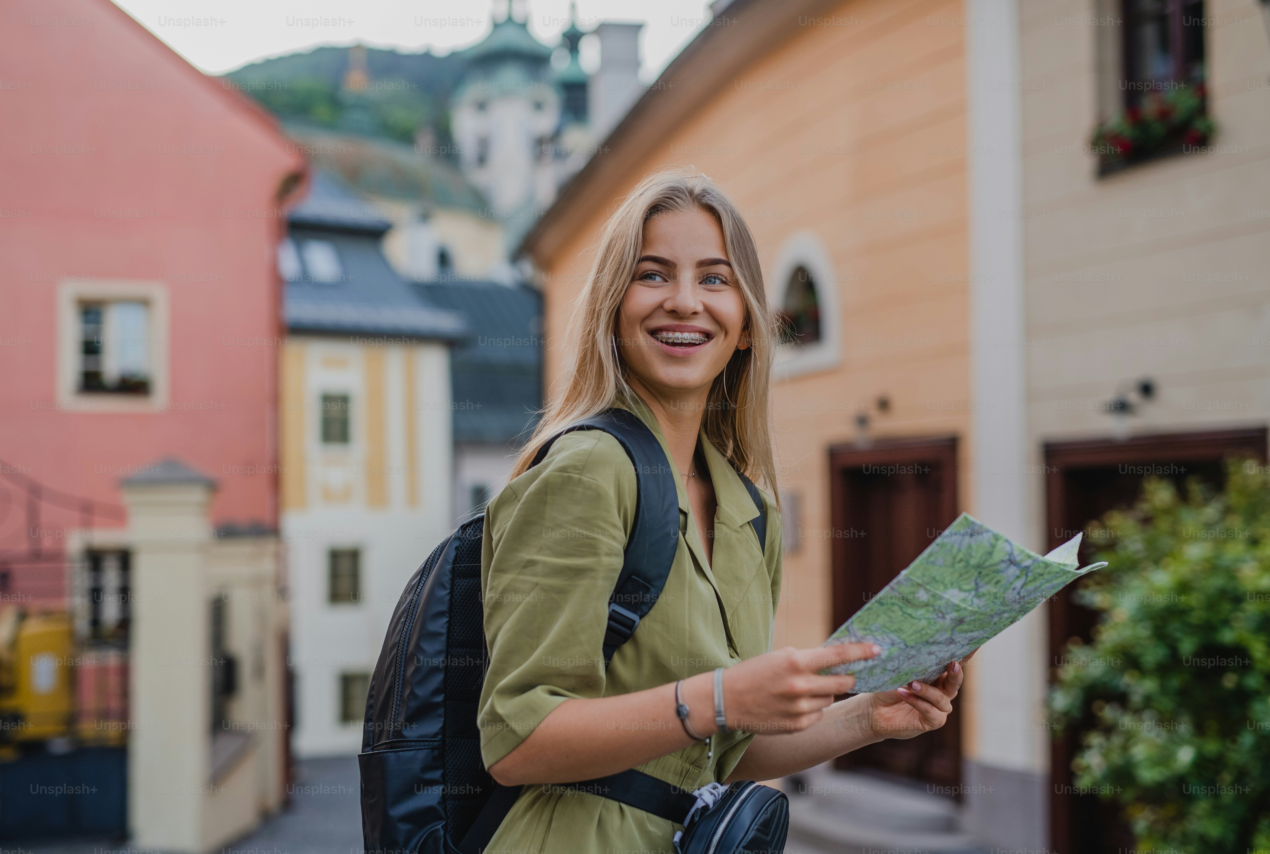A happy young woman tourist outdoors on trip in town, using map. photo ...