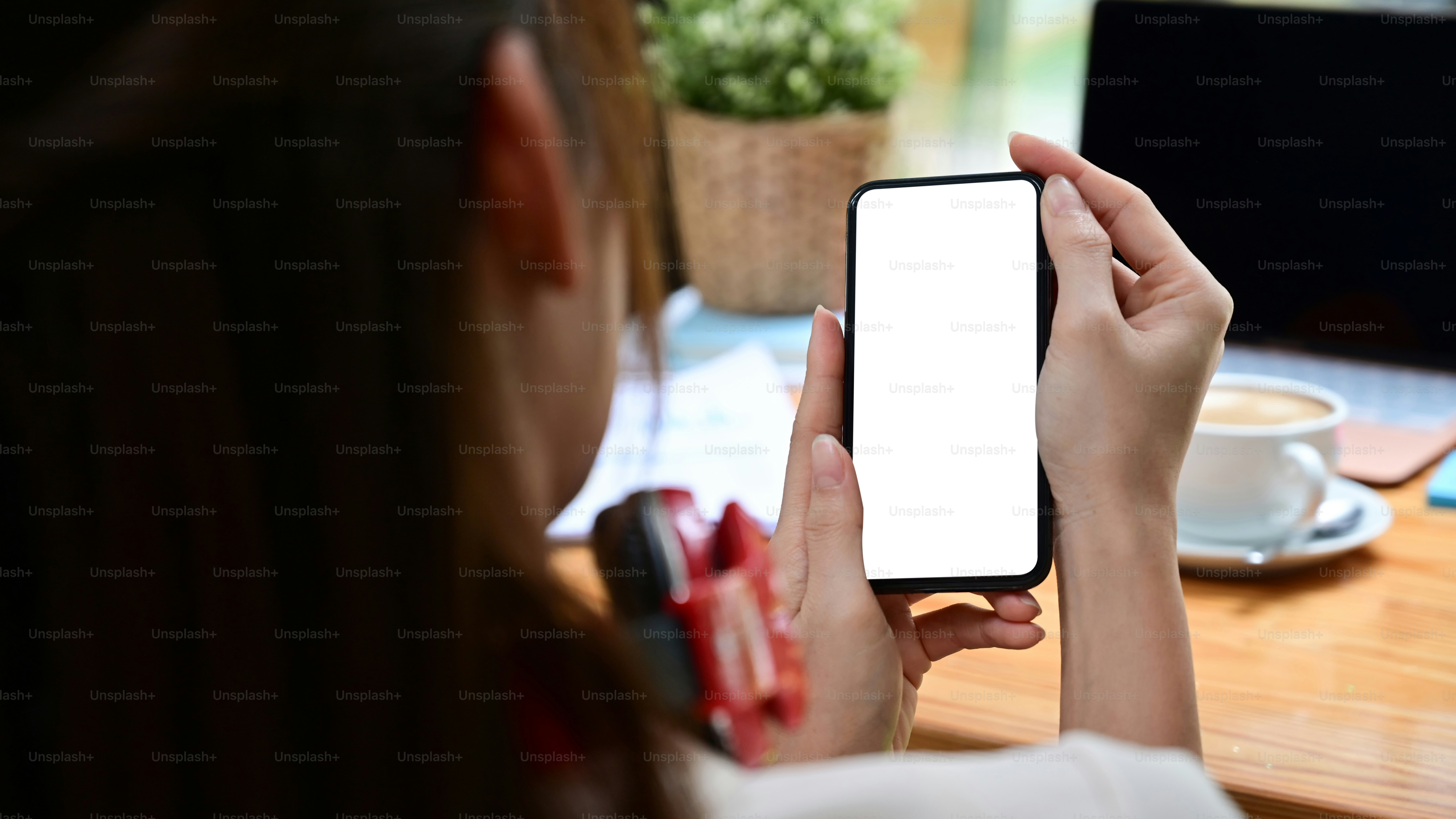 Rear view young female using smart phone at office desk. photo ...