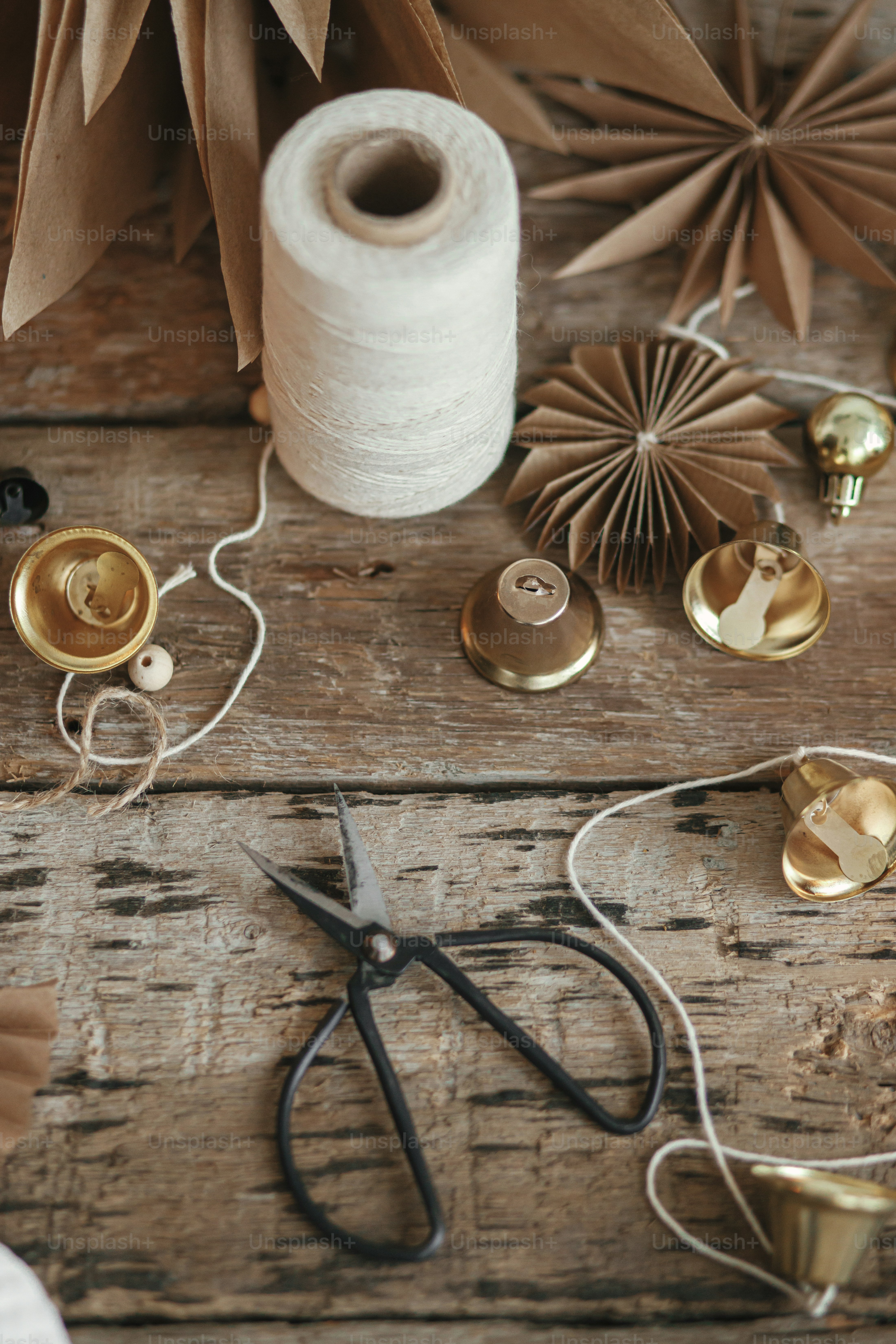 Stylish Christmas ornaments, bells, paper stars, thread, scissors on ...