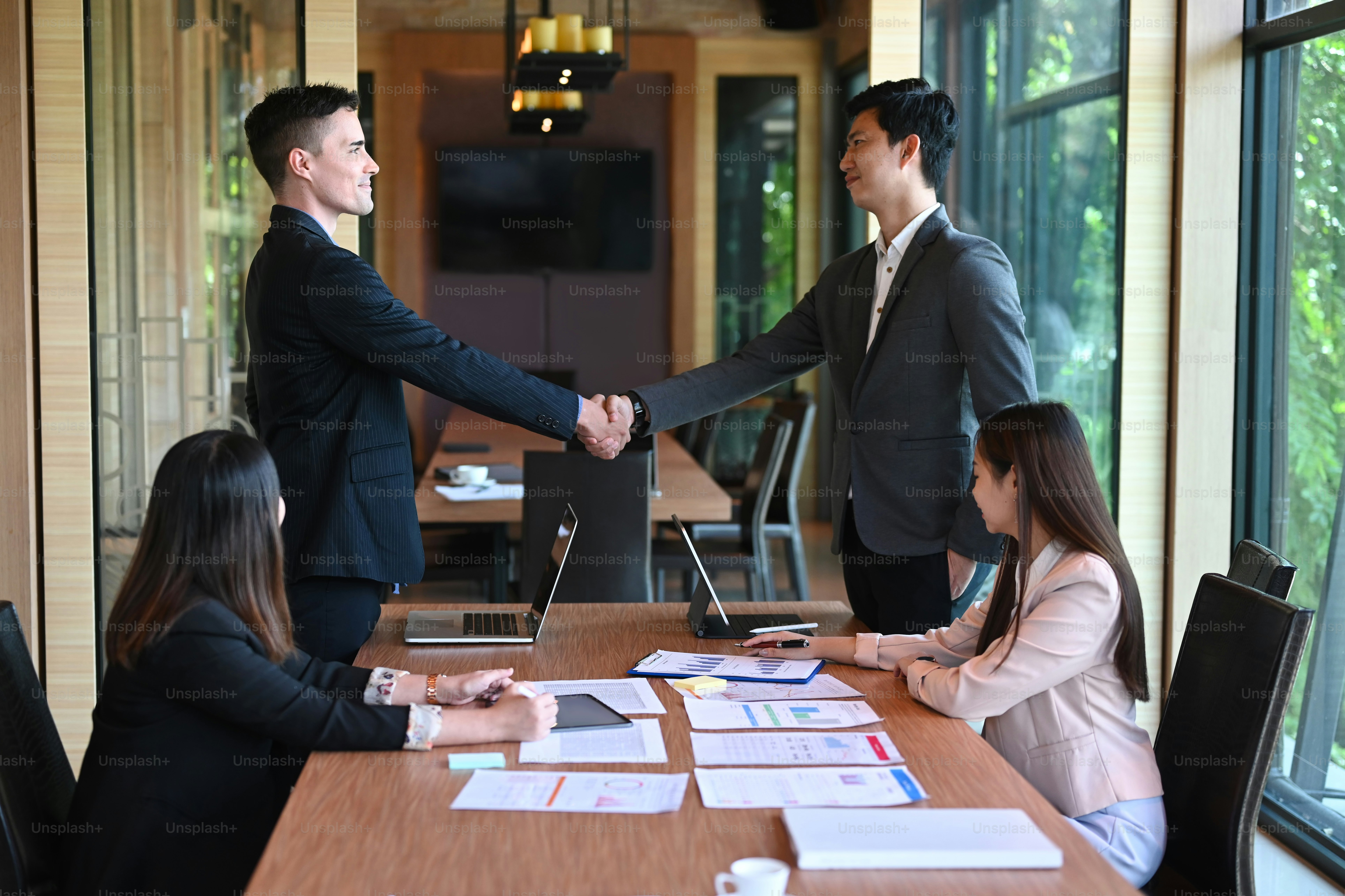 Successful businessmen handshaking over meeting table after negotiation ...