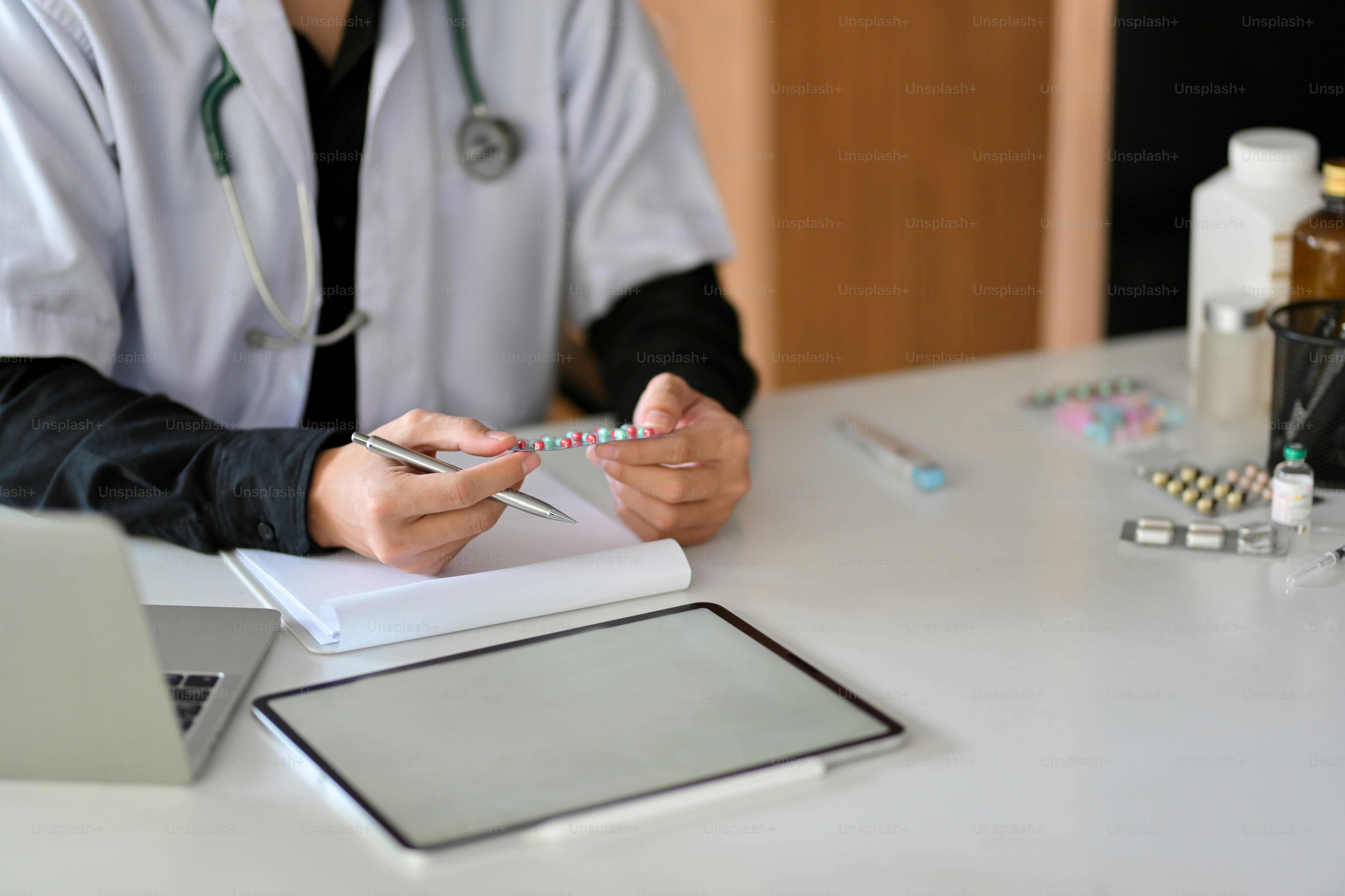 A young male intern doctor or pharmacist sits at his desk, looking at ...