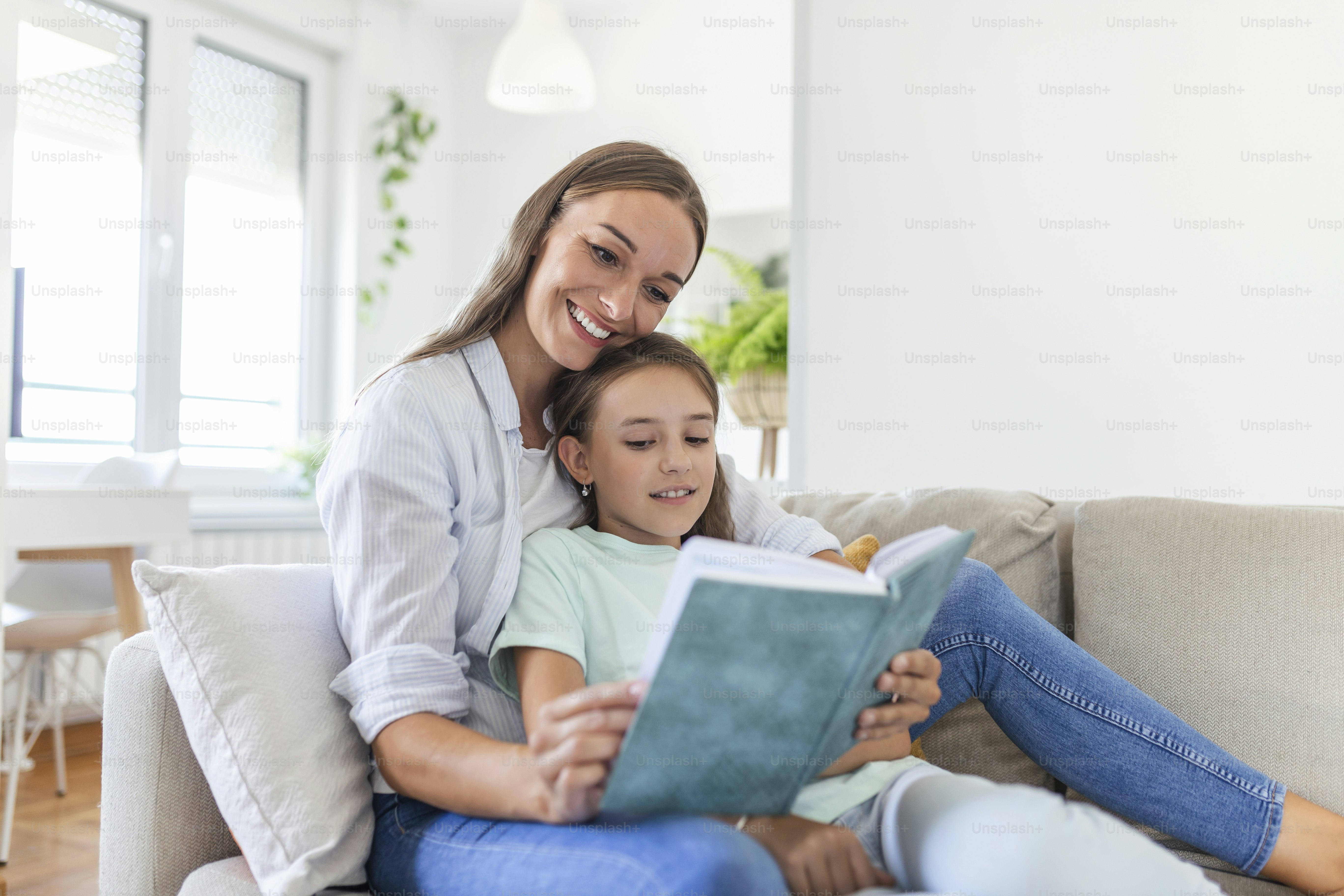 Loving young mother reading book to adorable little daughter, sitting ...