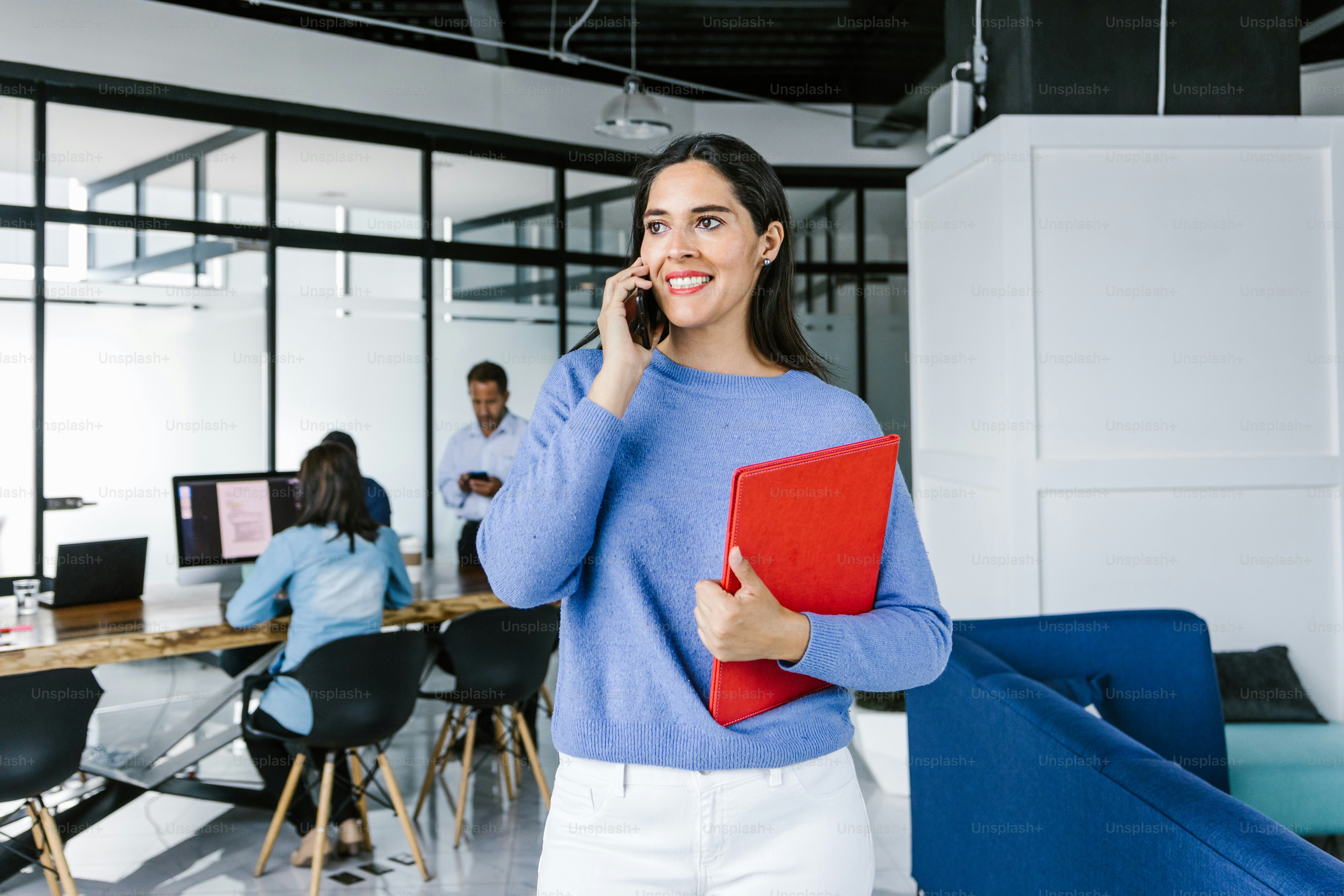 Young mexican female executive calling on the phone while holding a red ...