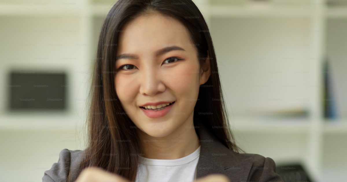 아름 다운 젊은 아시아 집 부동산 중개인의 초상화는 그녀의 책상에 앉아 집 열쇠 고리를 들고 있습니다 사진 Unsplash