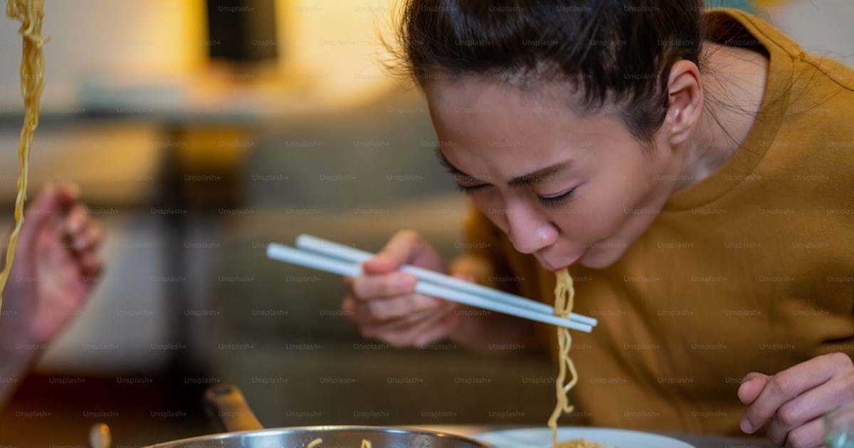 아름다운 아시아 여자 친구들은 소시지와 함께 인스턴트 라면을 먹고 밤에 거실에서 함께 이야기합니다 여성 커플 여자 친구는