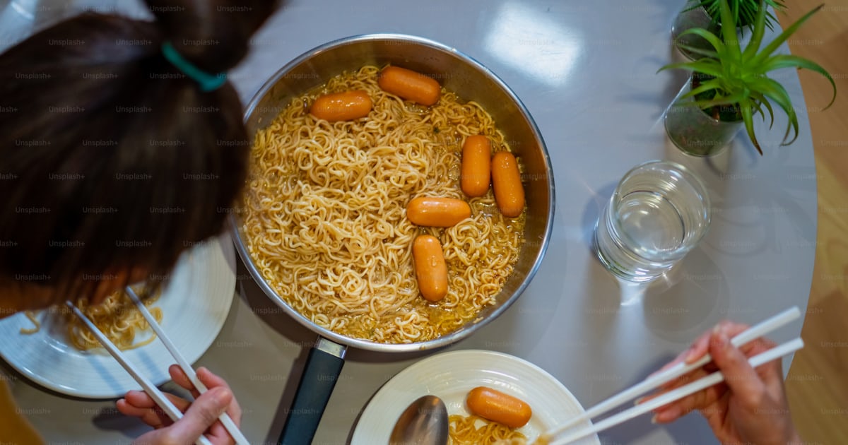 아름다운 아시아 여자 친구들은 소시지와 함께 인스턴트 라면을 먹고 밤에 거실에서 함께 이야기합니다 여성 커플 여자 친구는