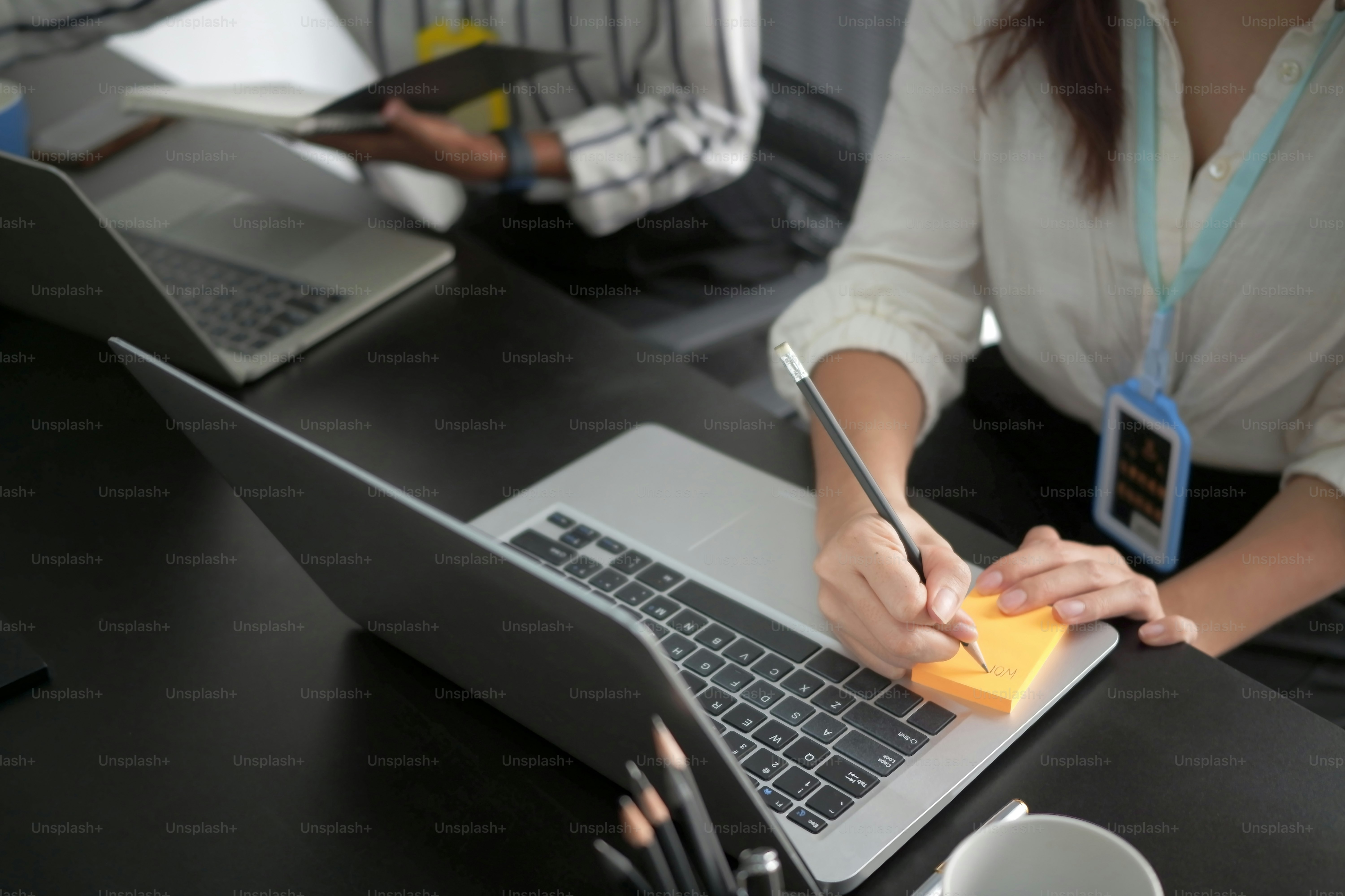 Female office worker working with laptop computer and making notes on ...