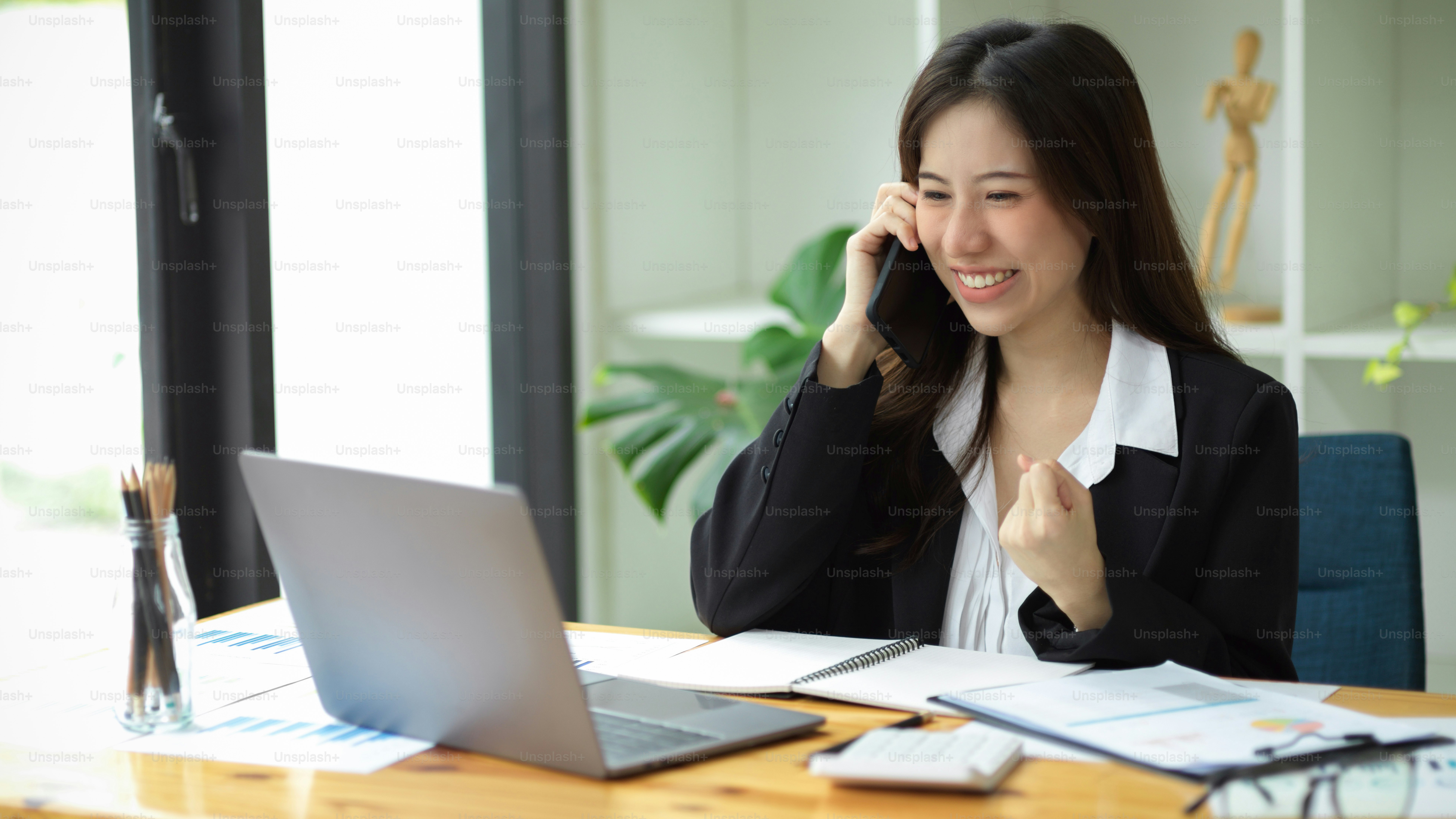 A happy young female employee received great news from her phone call ...