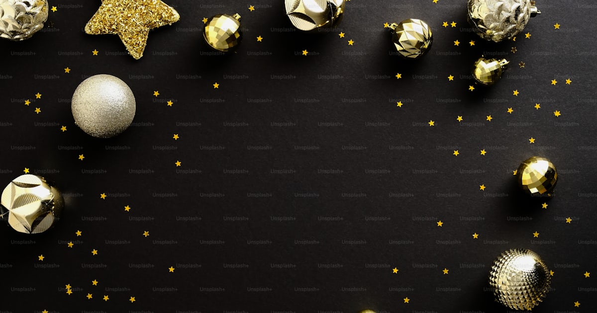 クリスマスの構図。暗い黒の背景に平らな横の金色のつまらないもの、星の装飾、紙吹雪。クリスマスグリーティングカードのデザイン、新年のバナー