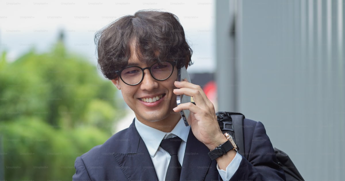 비즈니스 정장을 입은 아시아 사업가의 초상화는 자전거로 일하러 가는 동안 전화로 이야기합니다 사진 Unsplash의