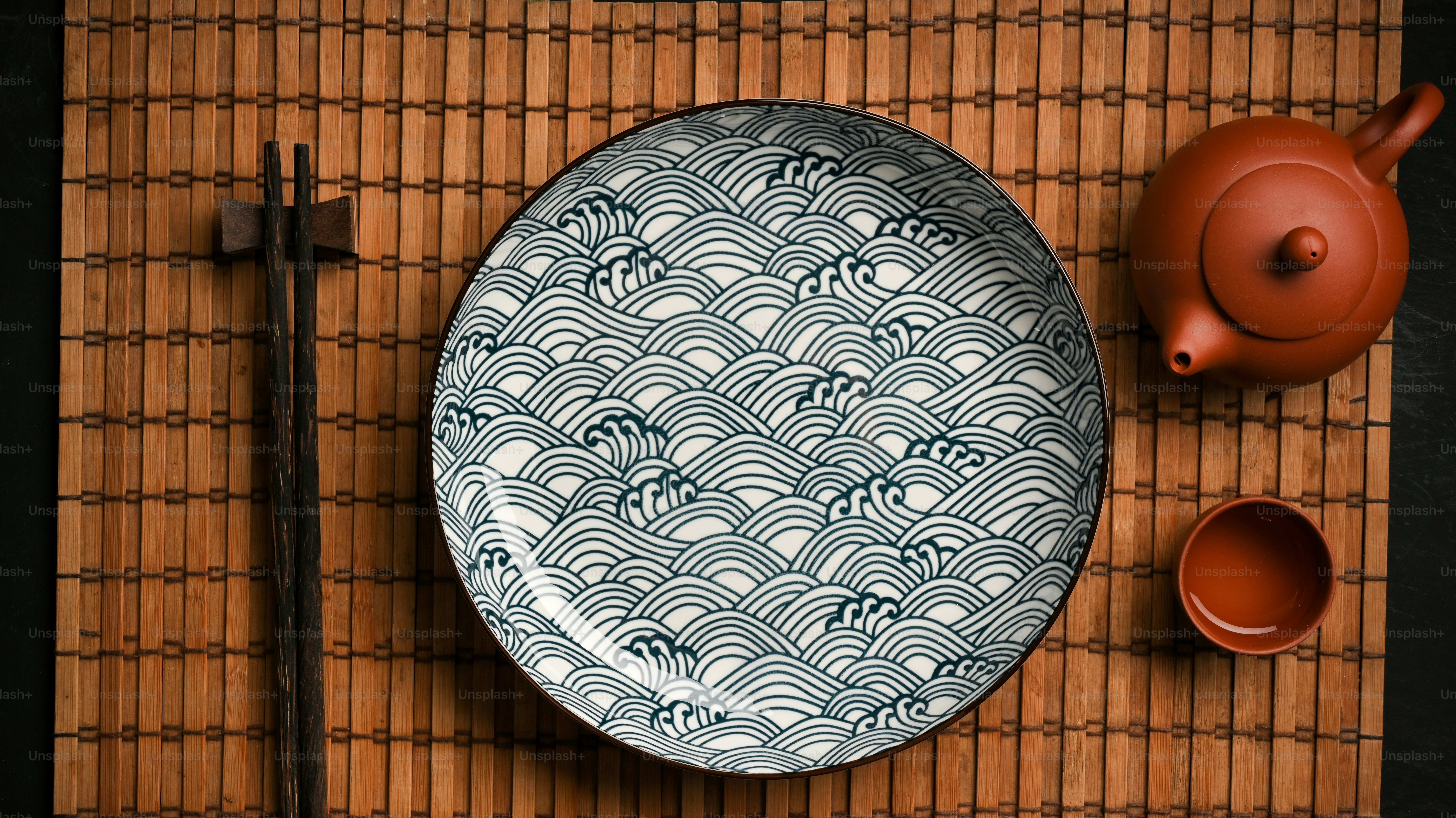 Asian crockery concept, ceramic plate with chopsticks on brown placemat ...