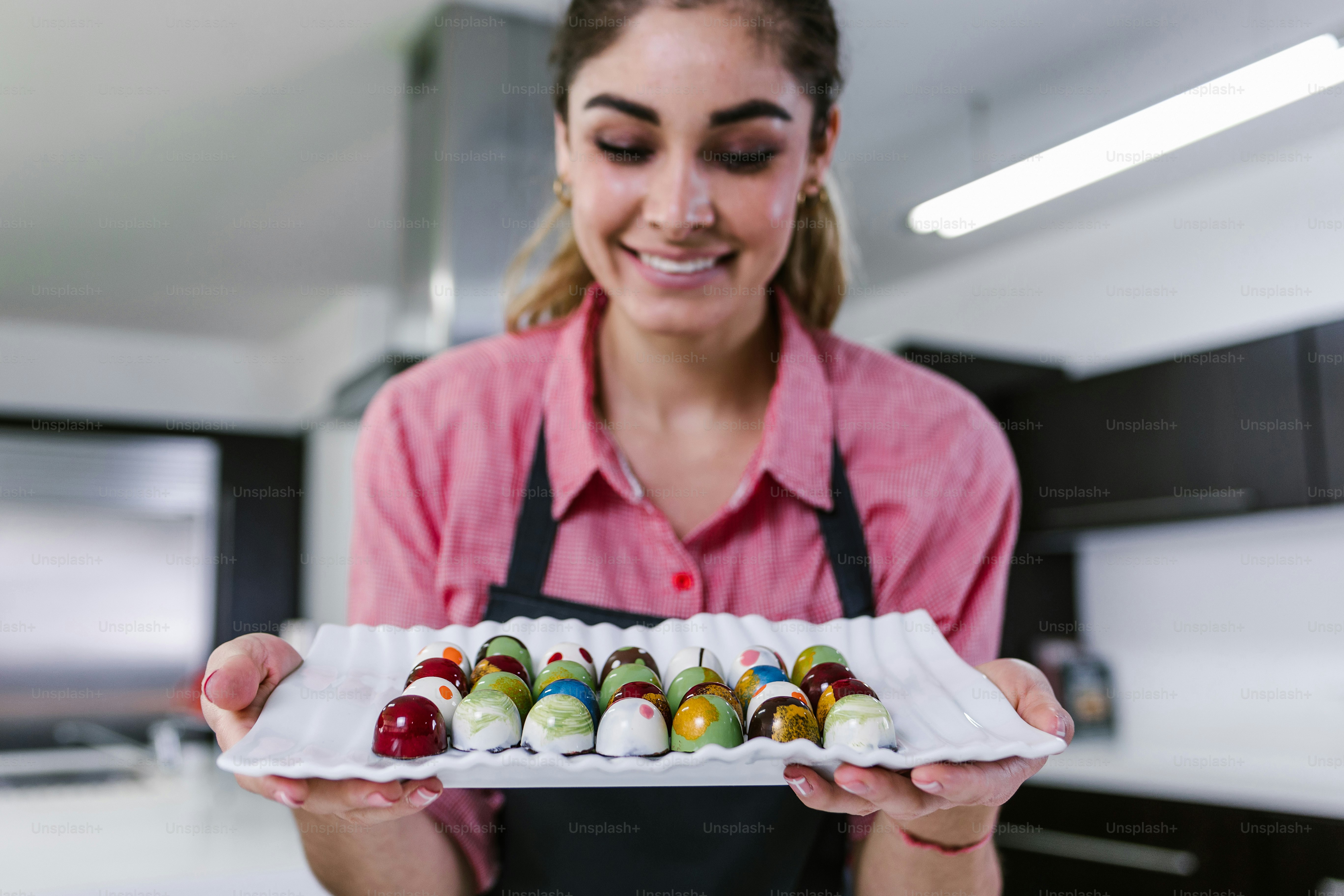 Joven latina chef pastelera preparando deliciosos dulces chocolates en ...