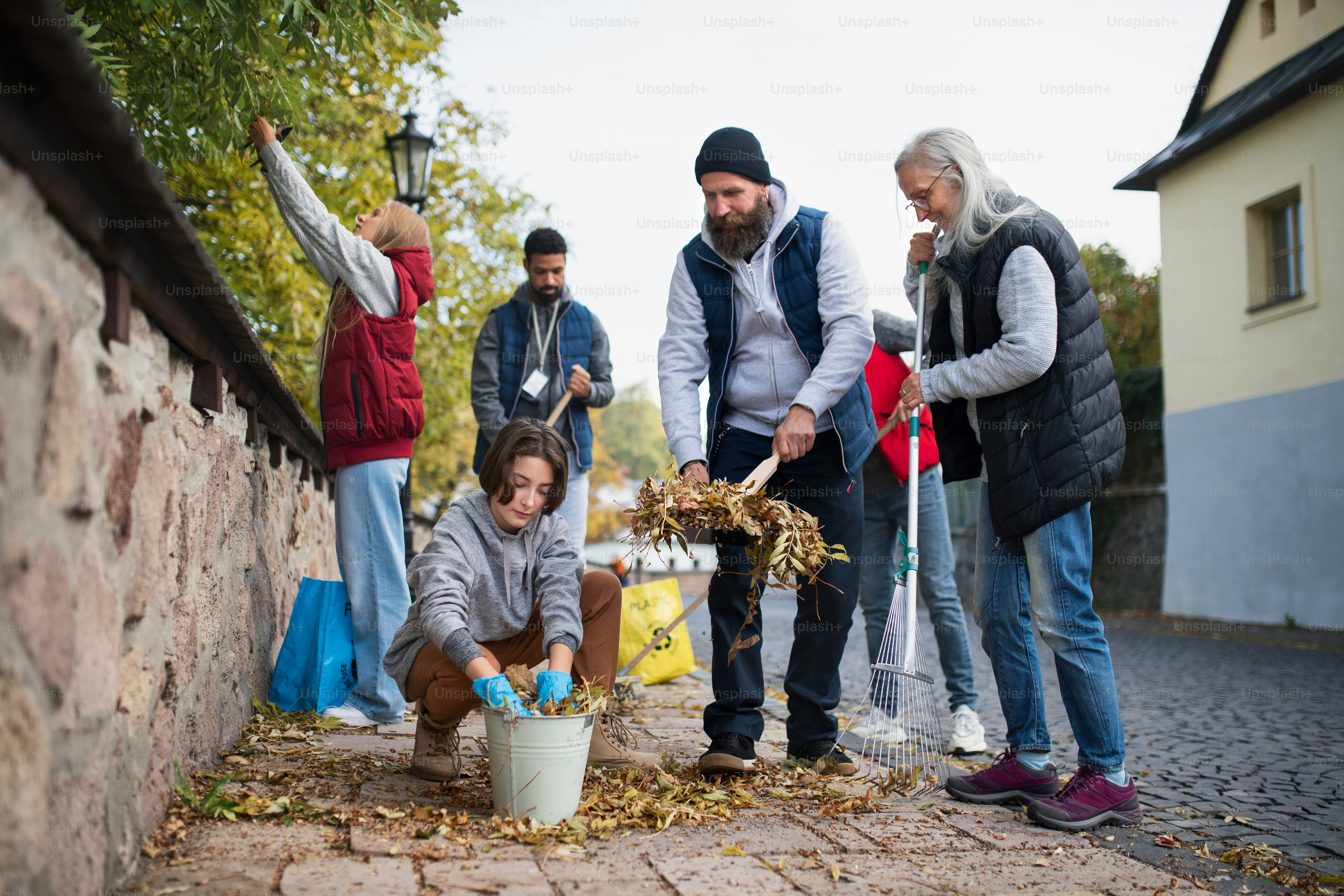 A diverse group of happy volunteers cleaning up street, community ...
