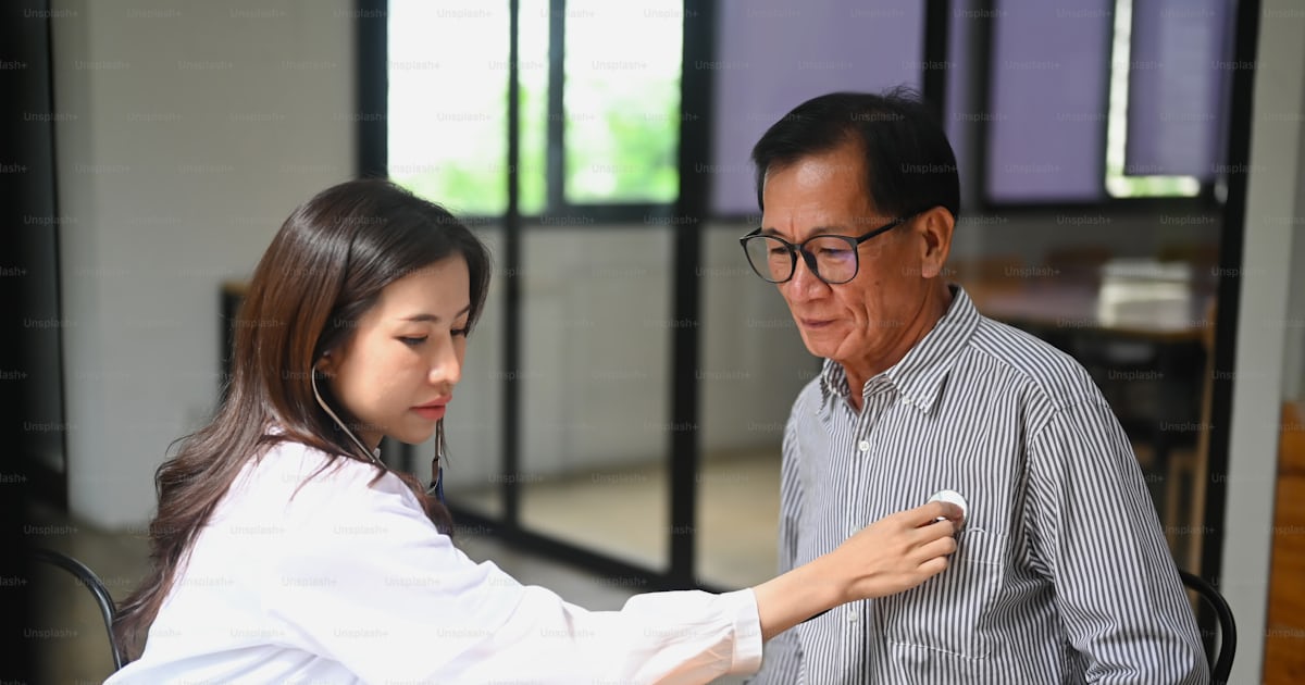 흰색 유니폼을 입은 여성 의사가 청진기를 사용하여 병실에서 검사하는 동안 노인 남성의 심장을 듣습니다 사진 Unsplash