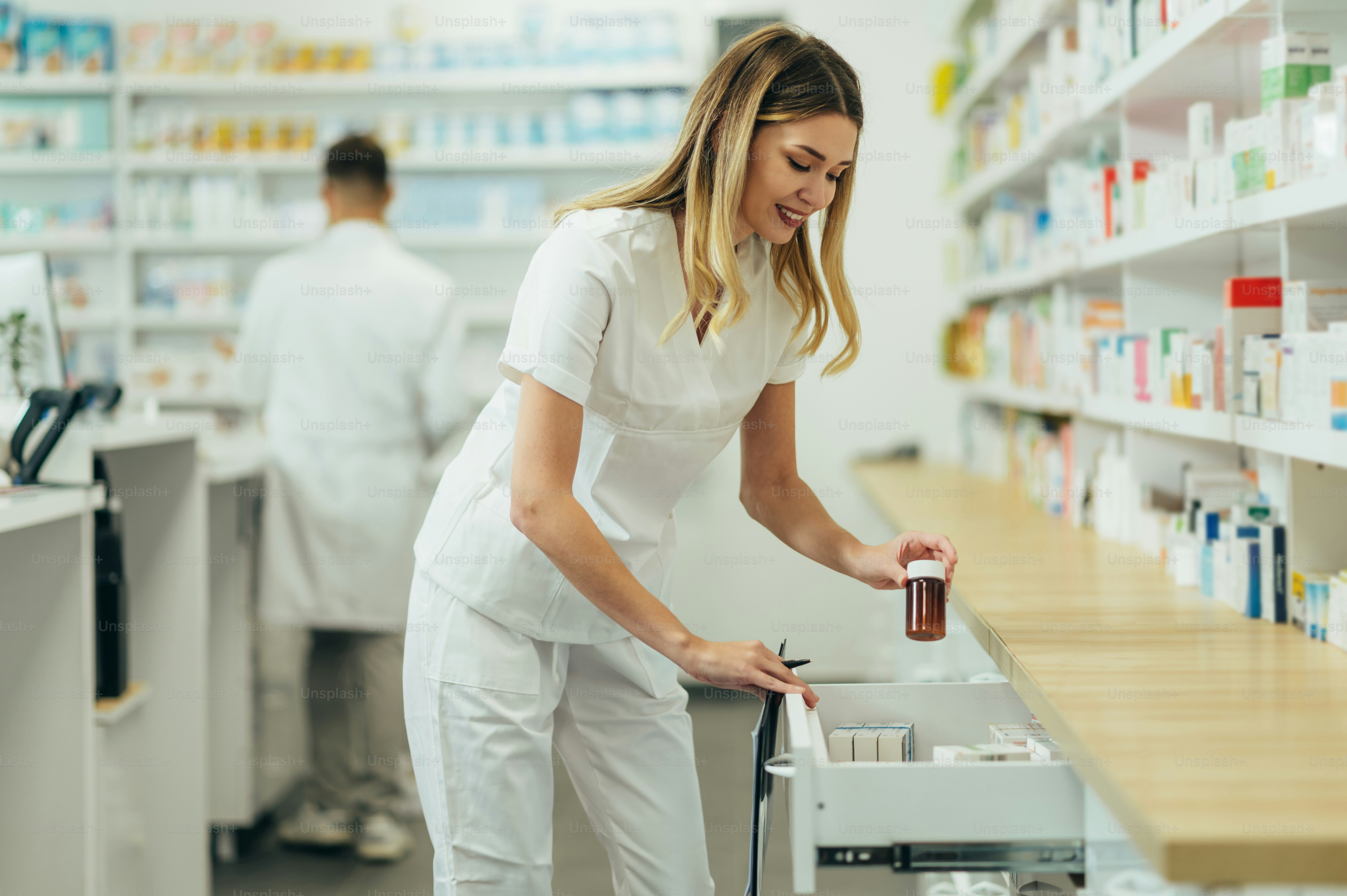 Beautiful female pharmacist working in a pharmacy while checking ...
