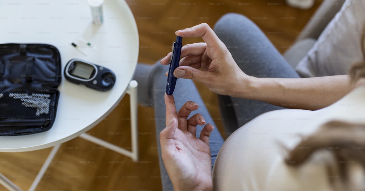 妊娠中の女性の糖尿病の血糖値をグルコメーターで検査します。砂糖のレベルを測定する準備ができて、指に血の 1 つの赤い滴。血の滴とテスト
