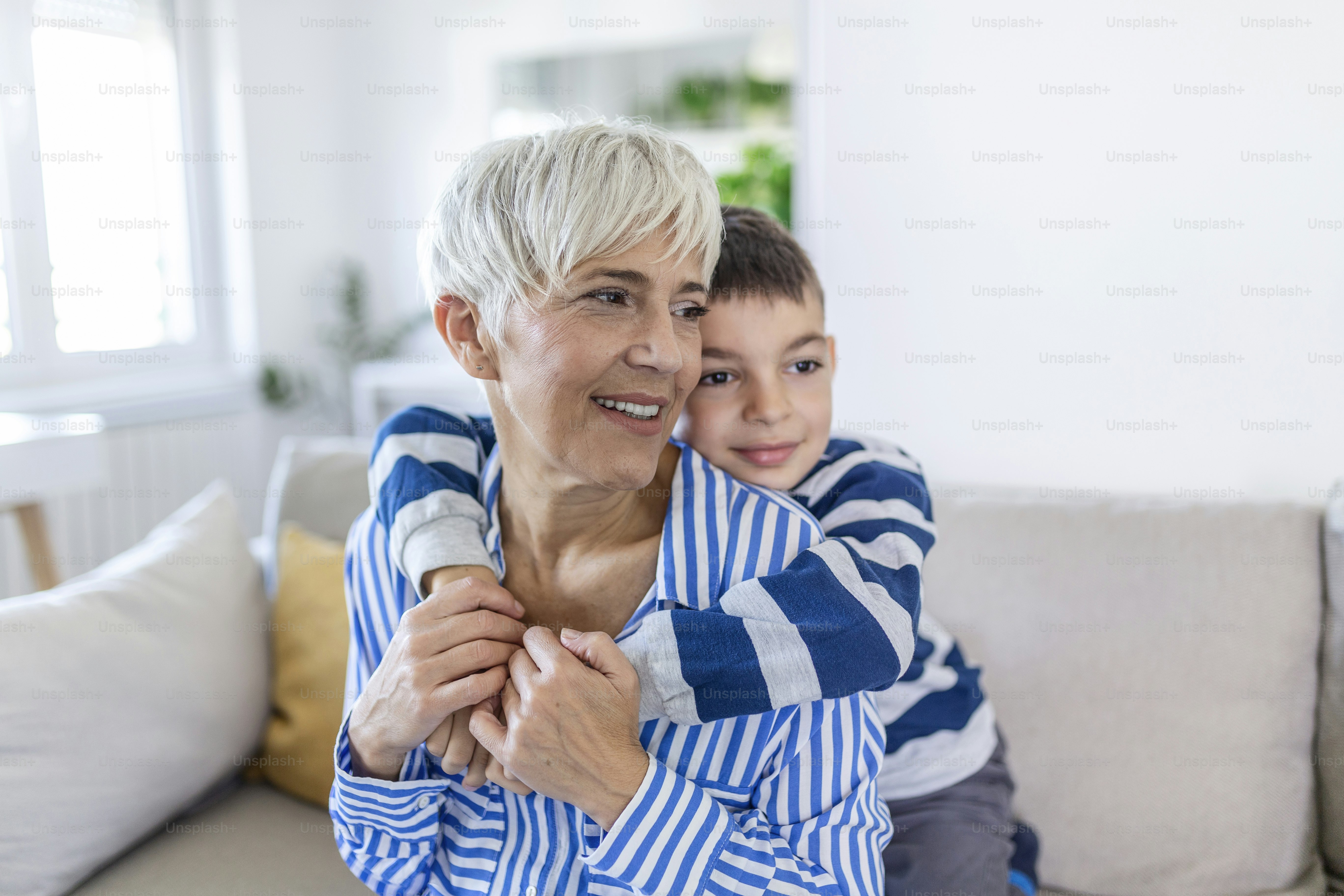 Happy senior grandmother sit on couch in living room hugging cute ...