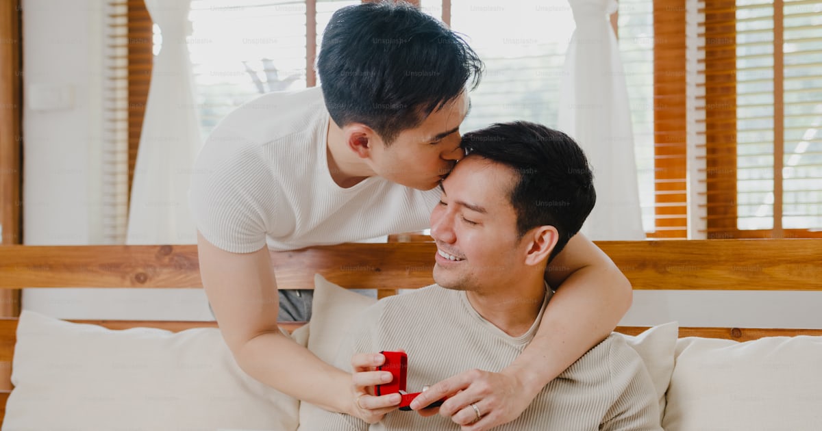 젊은 아시아 게이 커플은 현대 가정에서 프로포즈를 하고 행복한 미소를 짓는 Lgbtq 남성은 집 거실에서 결혼 반지를 끼고