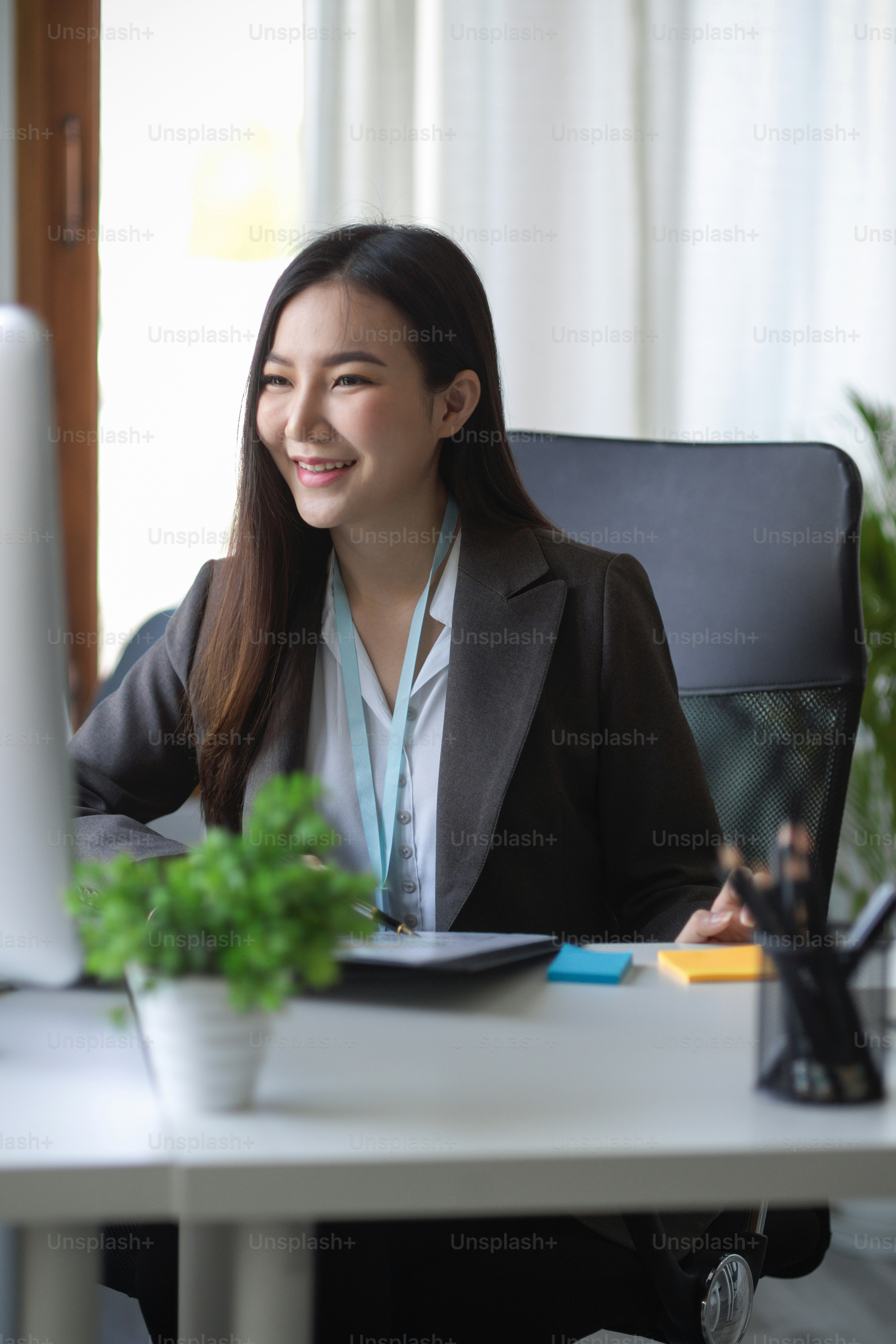 Foto Imagen de una joven, feliz y hermosa mujer de negocios sentada en la oficina usando una ...