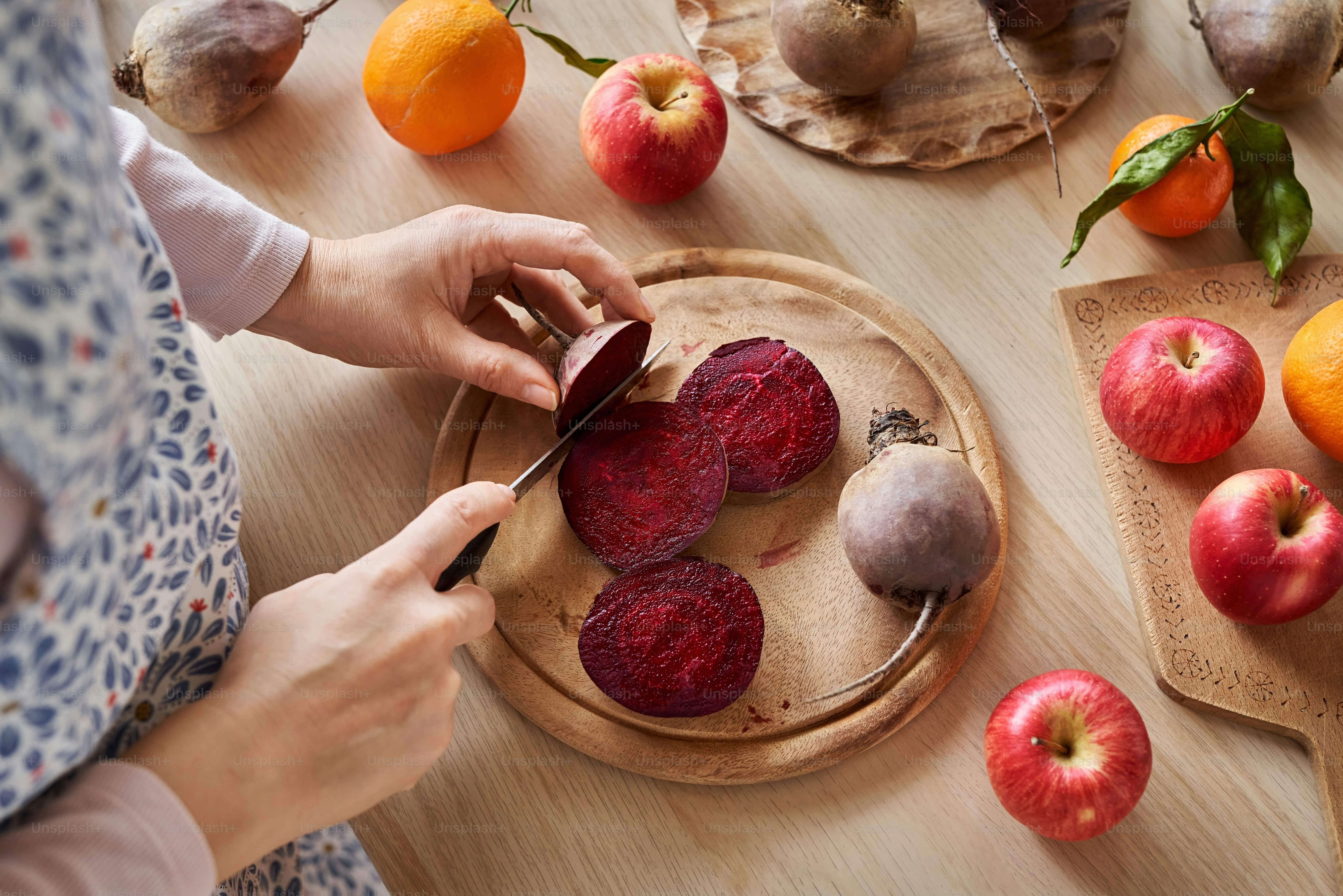 Woman cutting red beet root - preparation for juicing fresh fruits and ...