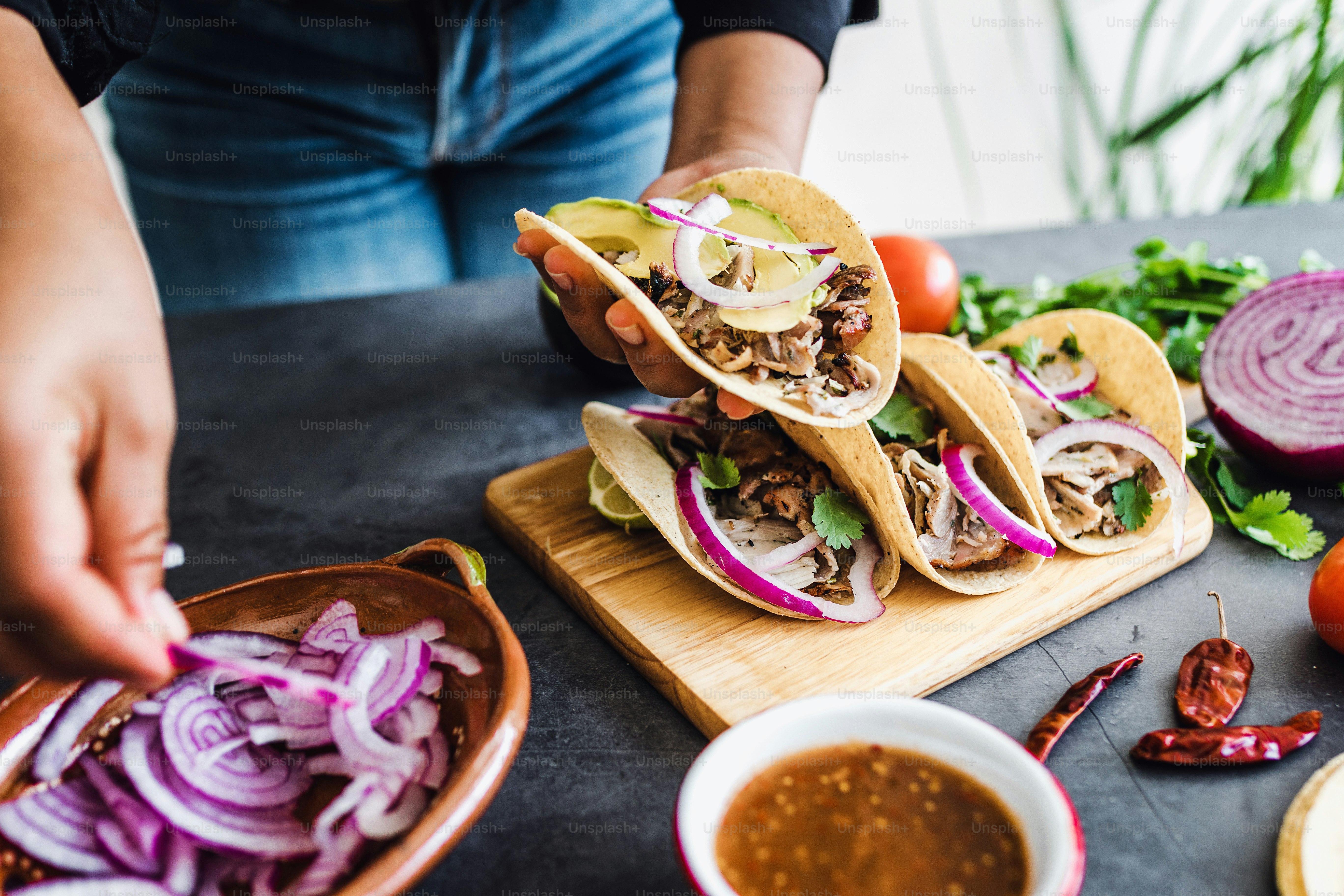 Manos de mujer latina preparando tacos mexicanos con carnitas de cerdo ...