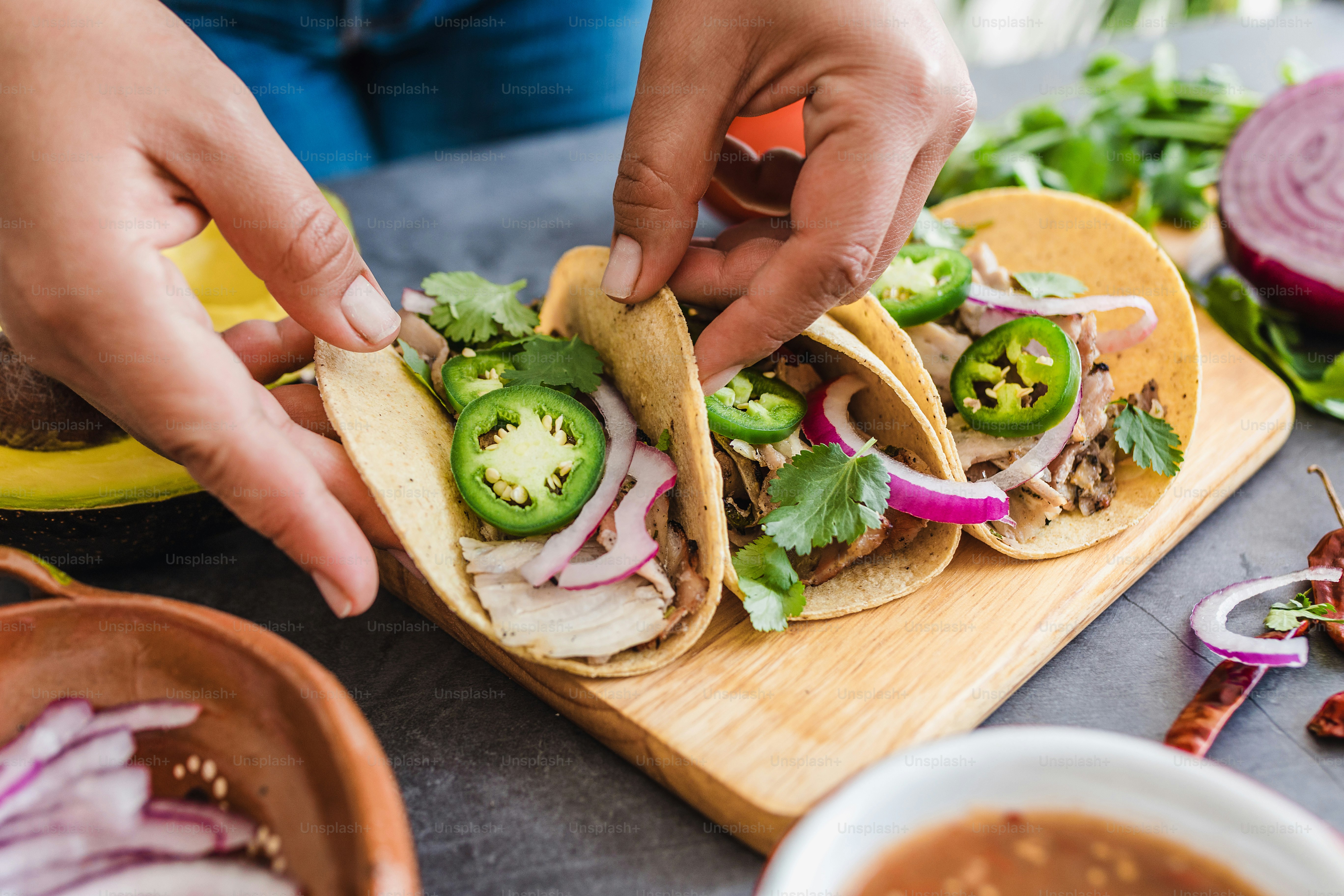 Latin woman hands preparing mexican tacos with pork carnitas, avocado ...