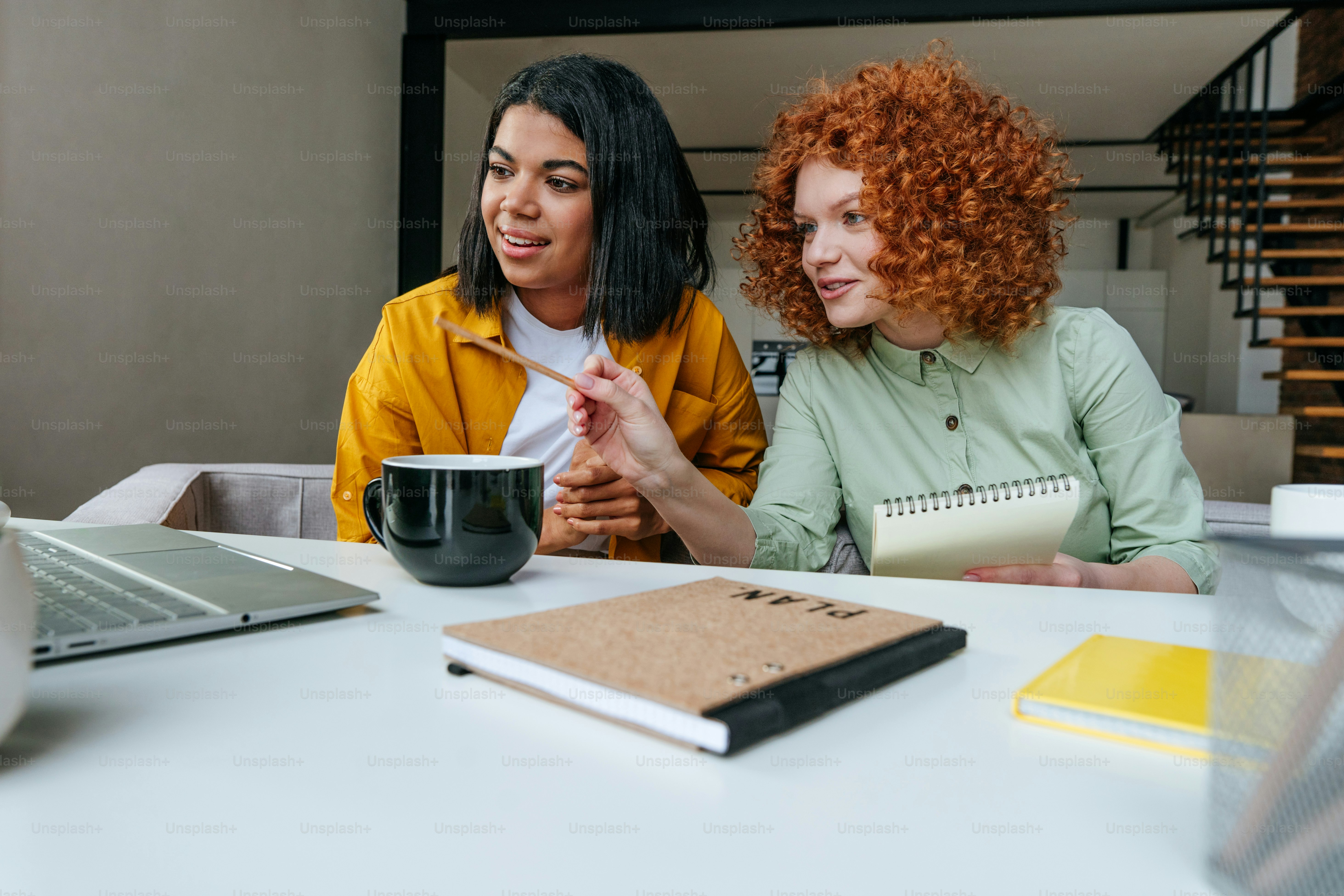 Zwei junge Frauen, die einen Laptop für Videoanrufe benutzen, sitzen ...