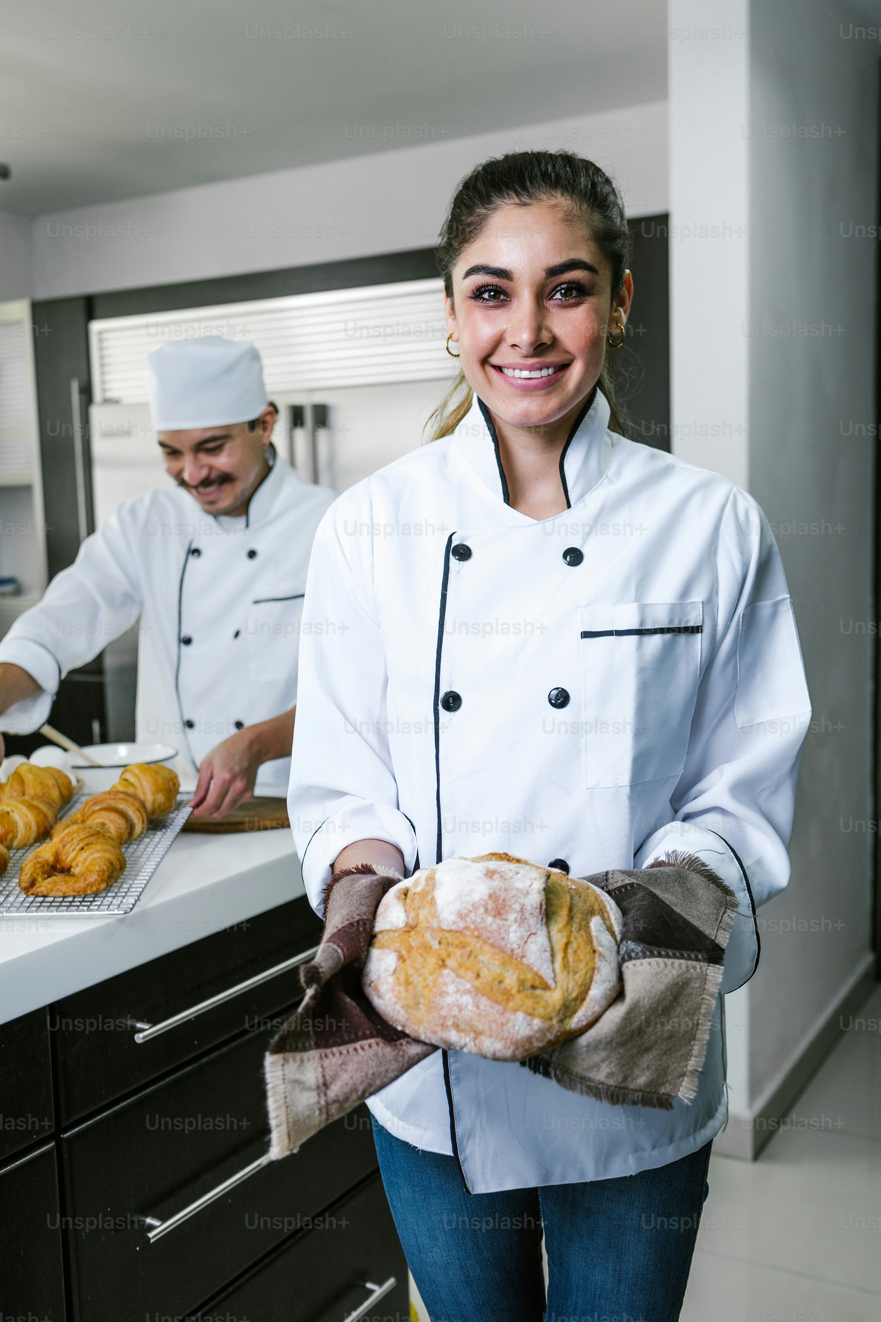 Young Latin woman baker holding piece of bread at kitchen in Mexico ...