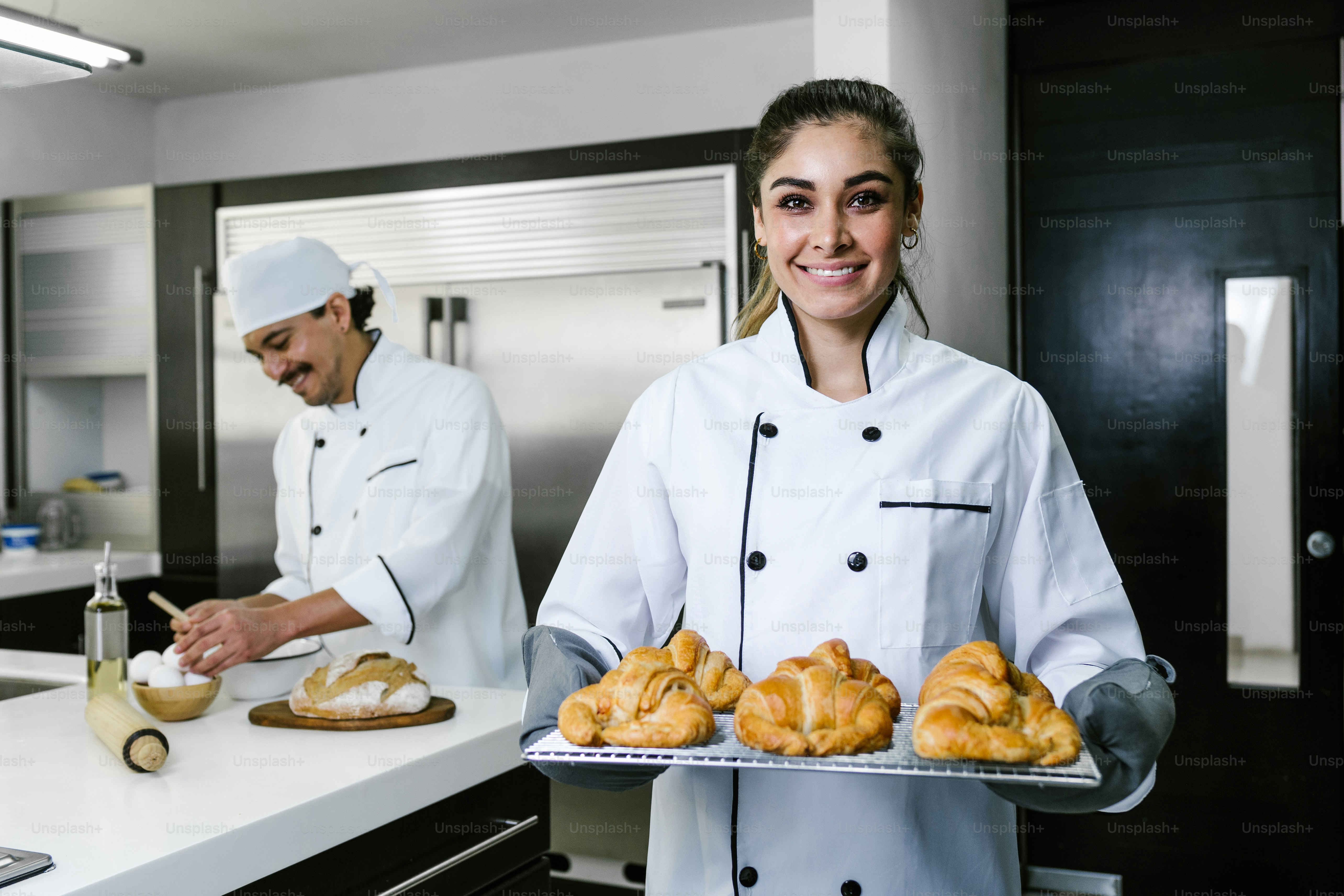 Young Latin woman baking croissant bread on oven at kitchen in Mexico ...