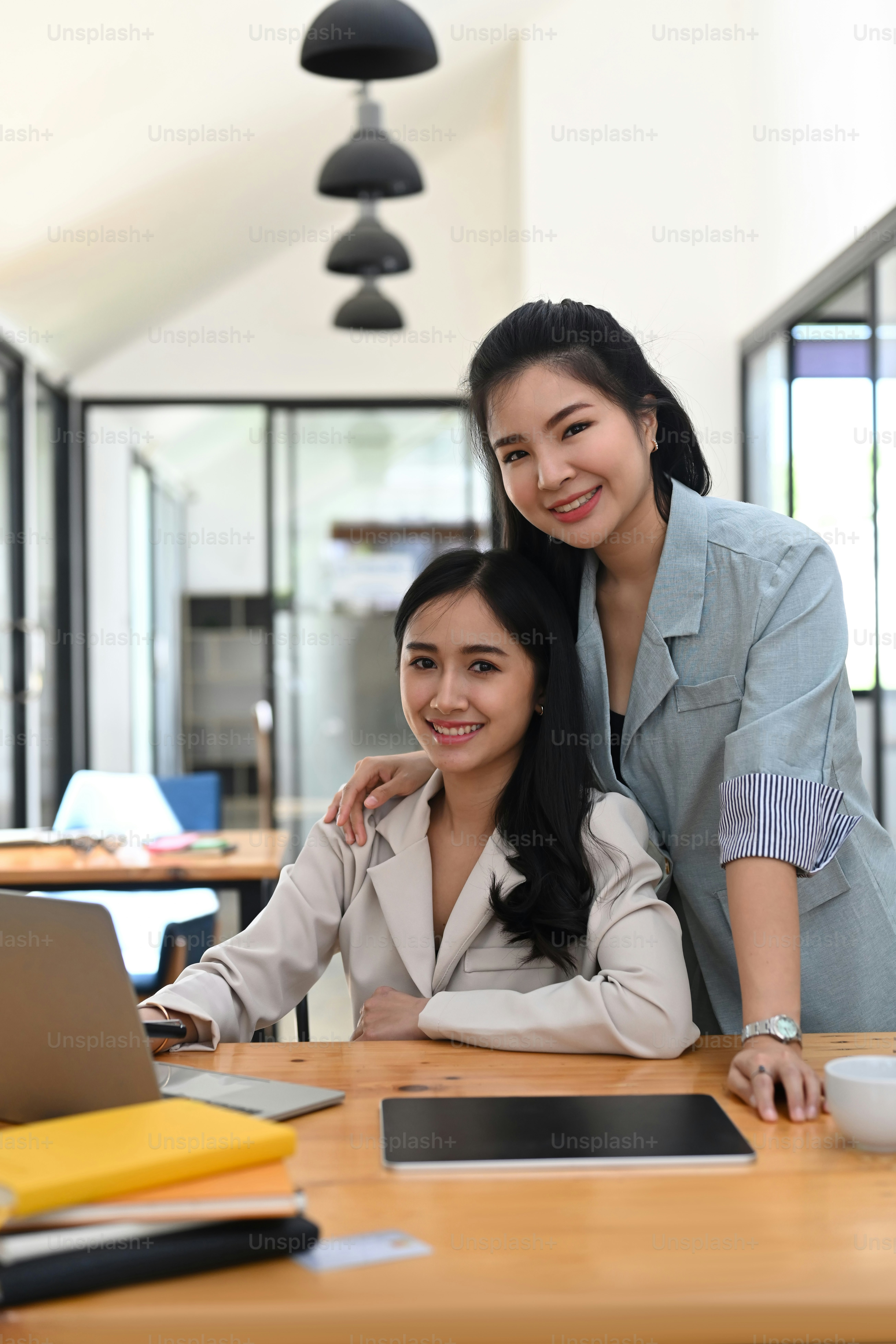 Two cheerful female business colleagues working together at modern ...