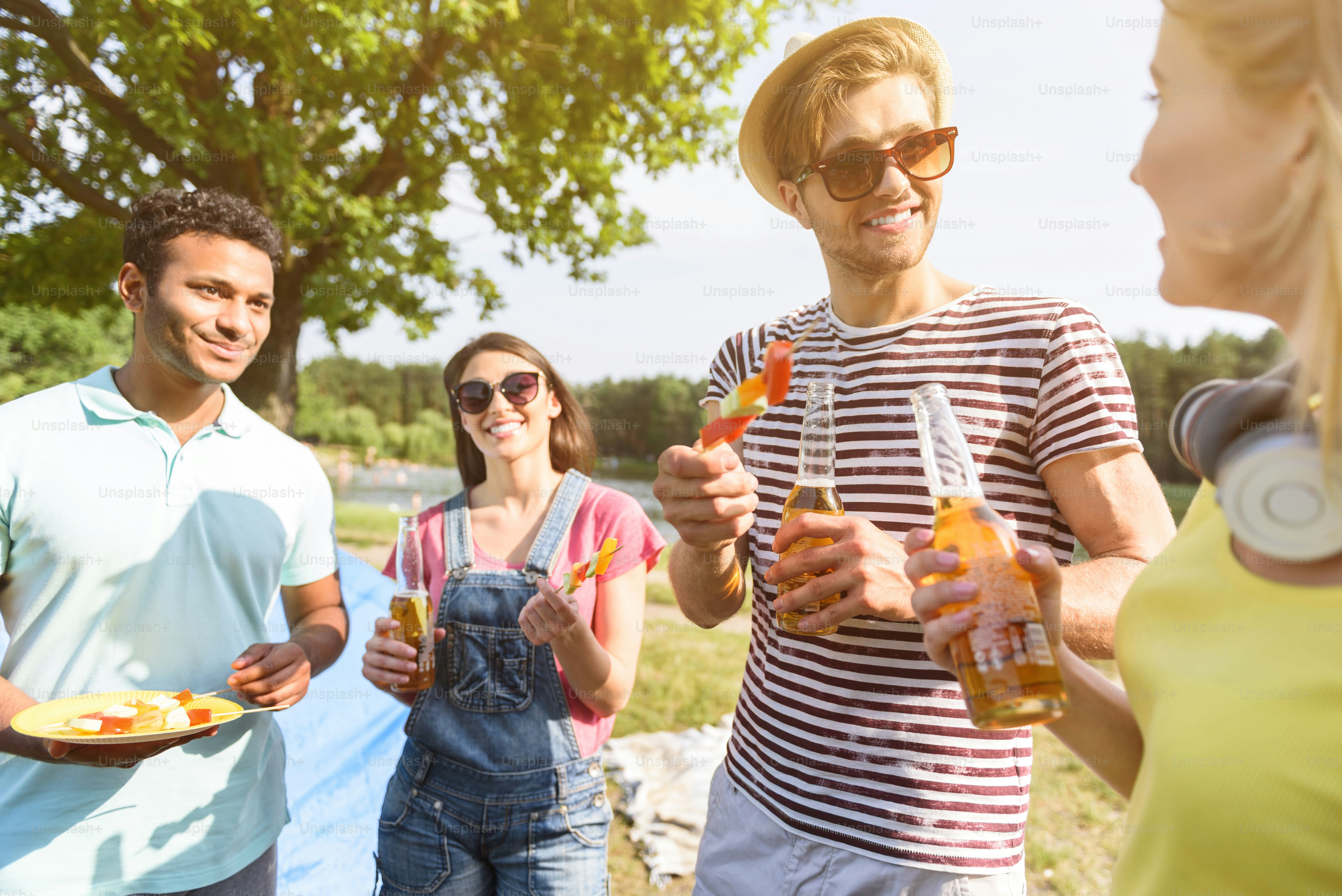 Cheerful young friends are making picnic in the nature. They are eating ...