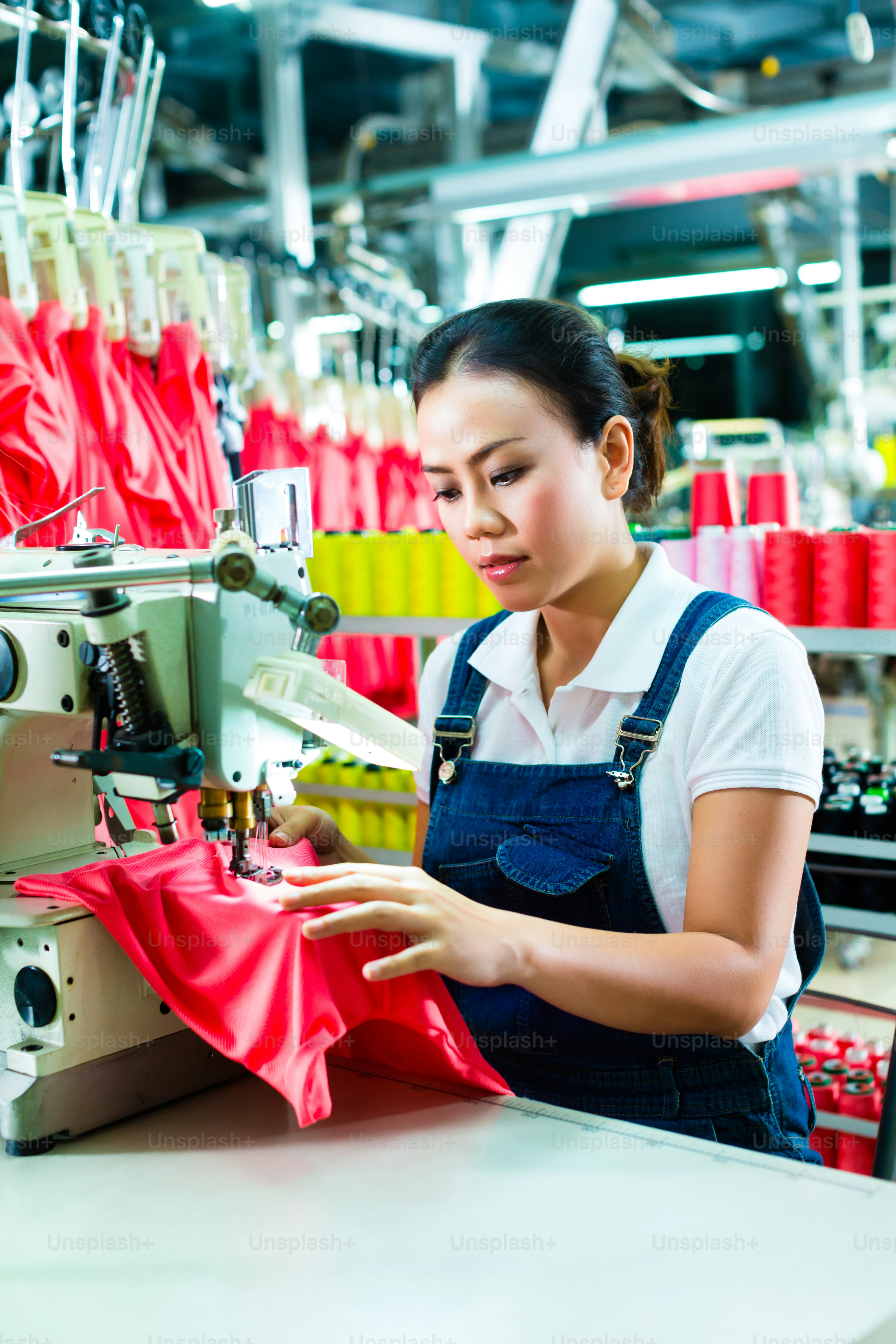 Seamstress or worker in factory sewing with industrial machine, she is ...