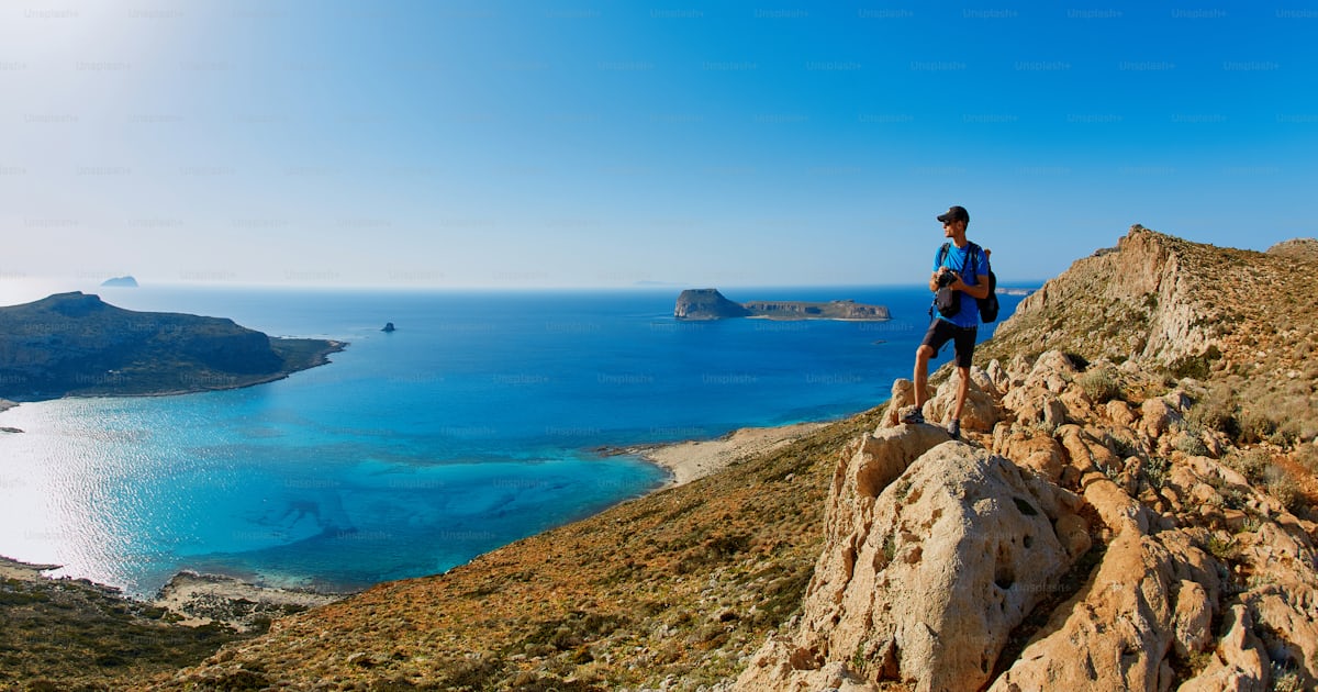 ギリシャ、クレタ島のバロスビーチのパノラマビュー。崖の上に立つ男、旅人、写真家の写真 Unsplashのクレタ島の画像