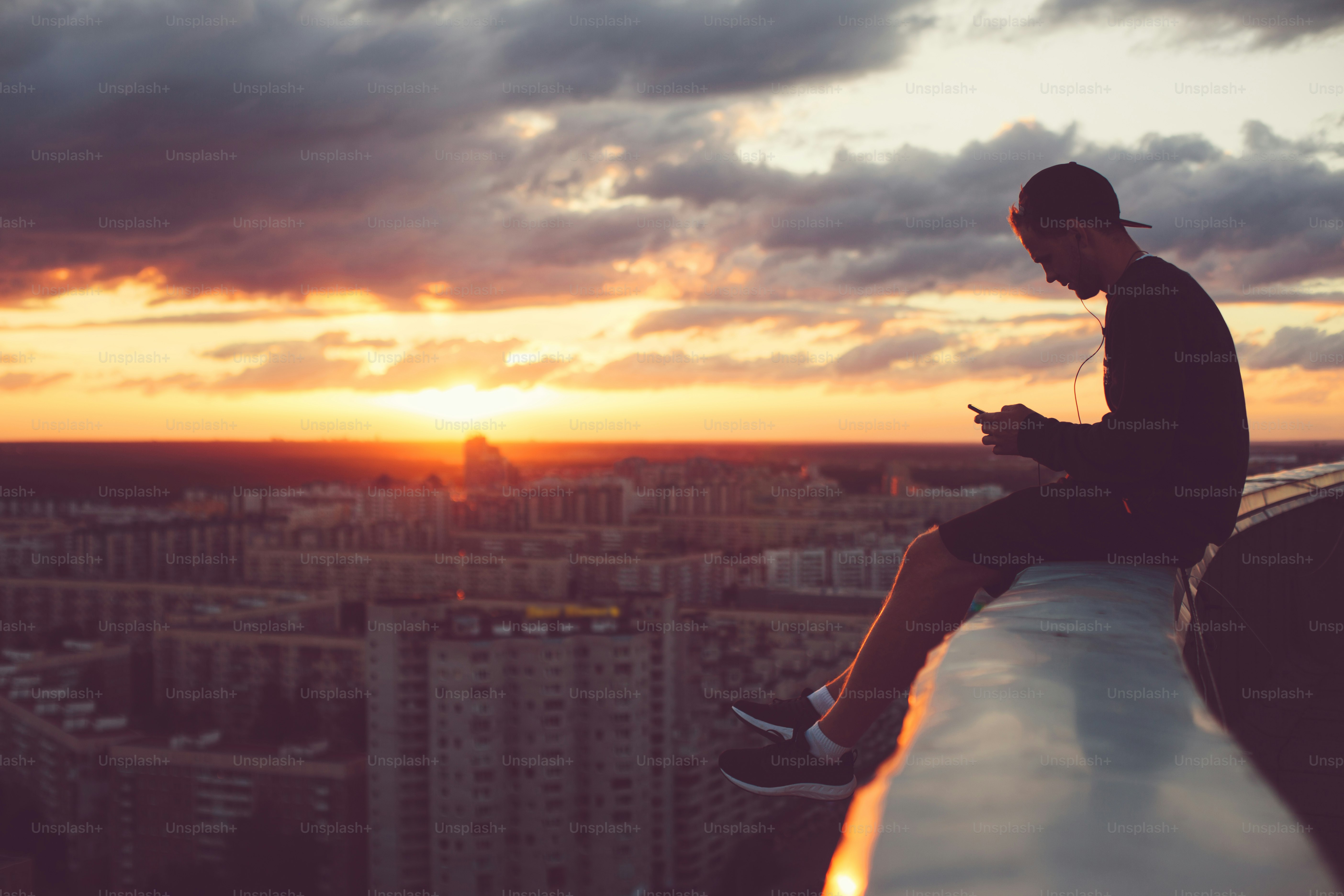 Foto Joven valiente sentado sobre la ciudad con teléfono inteligente al ...