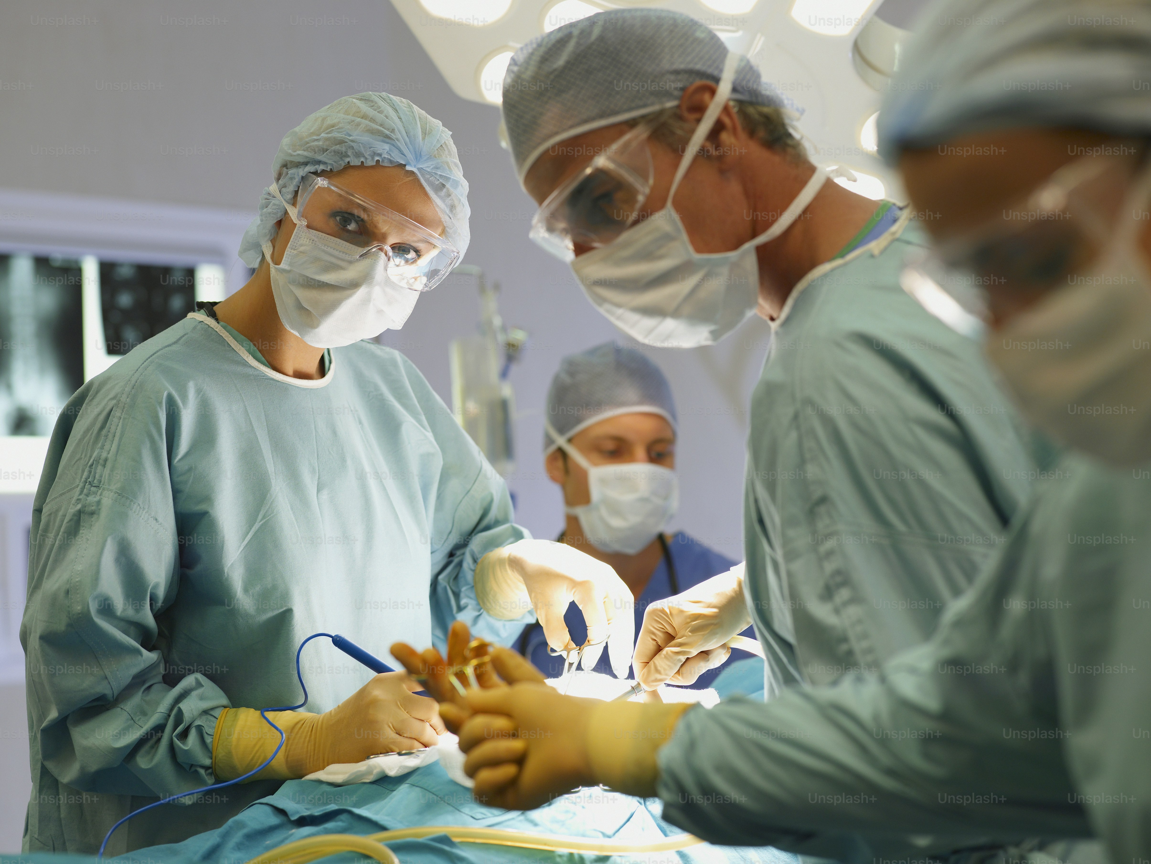 A group of doctors performing surgery on a patient photo – Day Image on ...