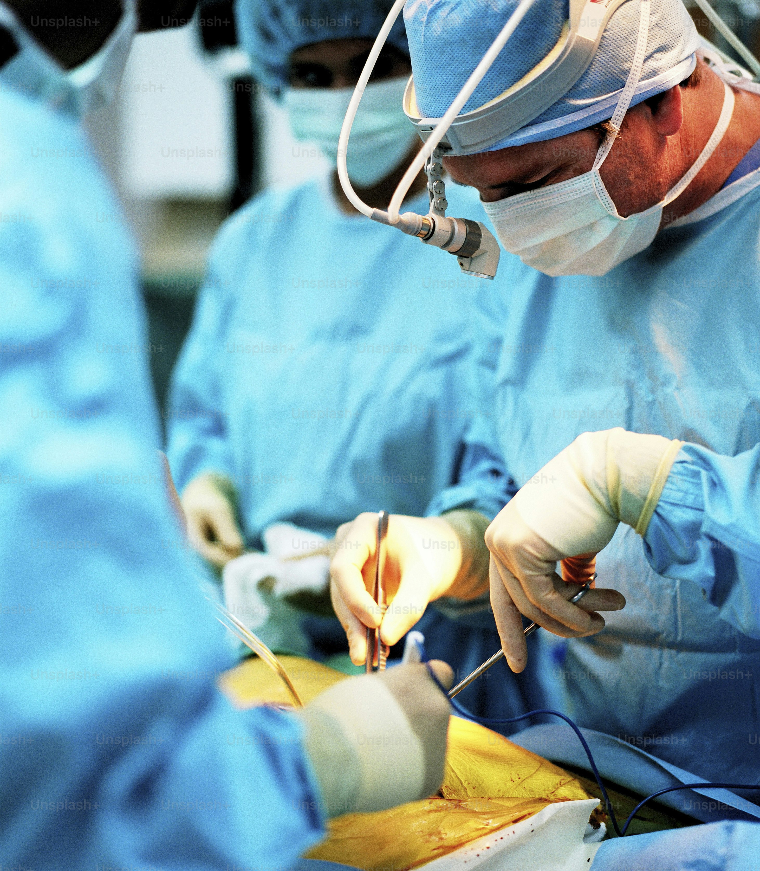 A group of doctors performing surgery on a patient photo – Doctor Image ...