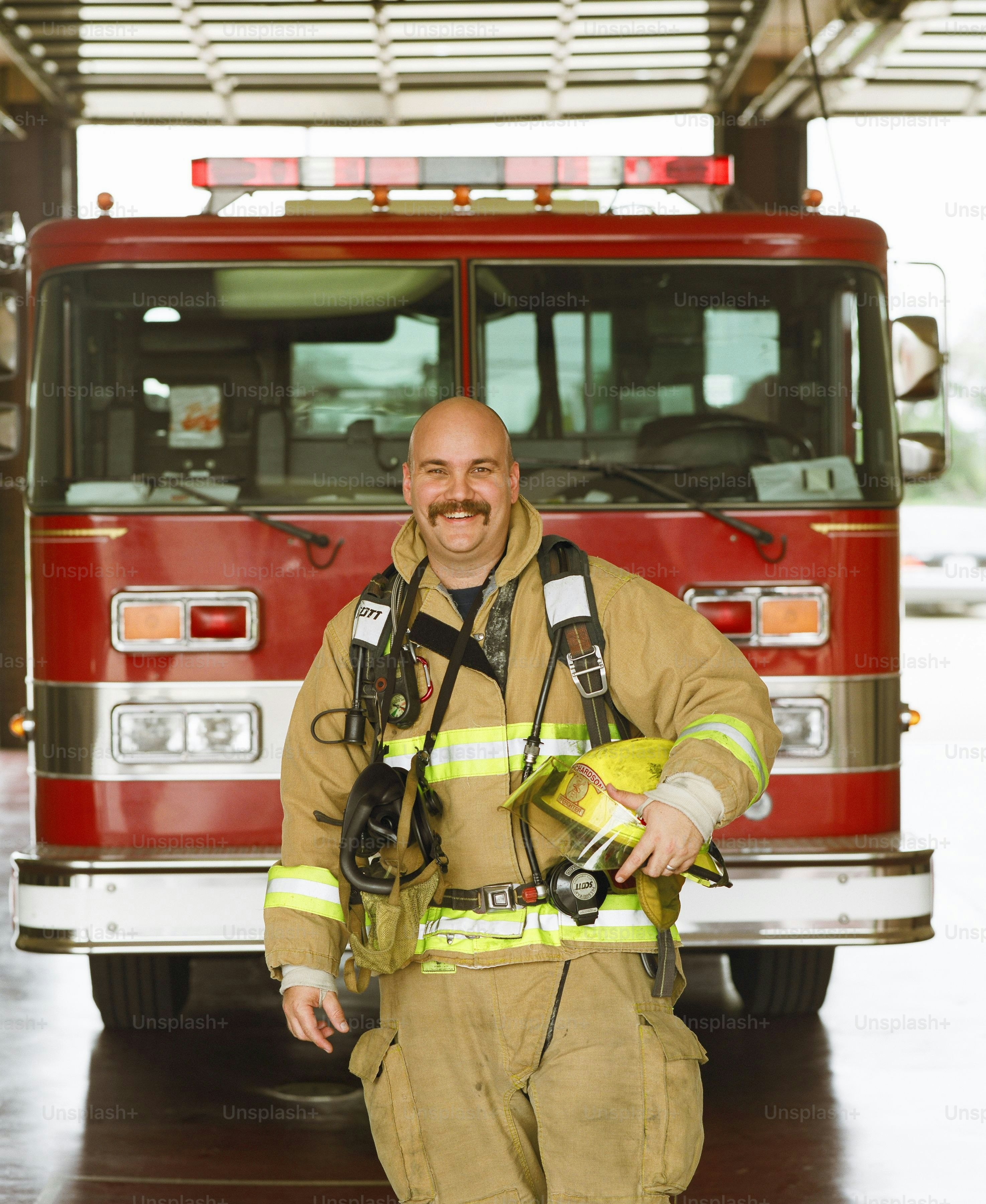 A firefighter standing in front of a fire truck photo – Fire truck ...