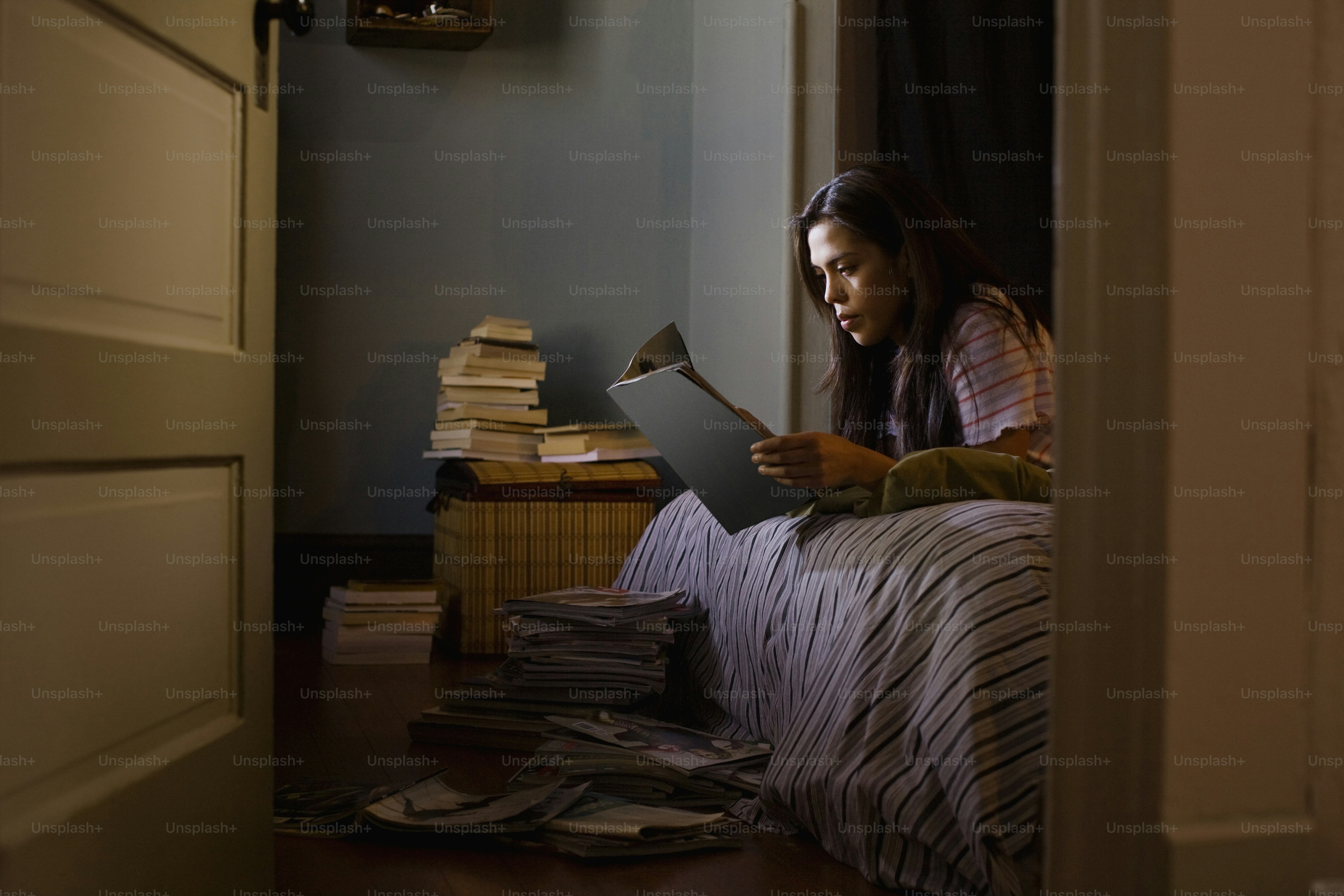 Girl reading magazines in her bedroom at night photo – One person Image ...