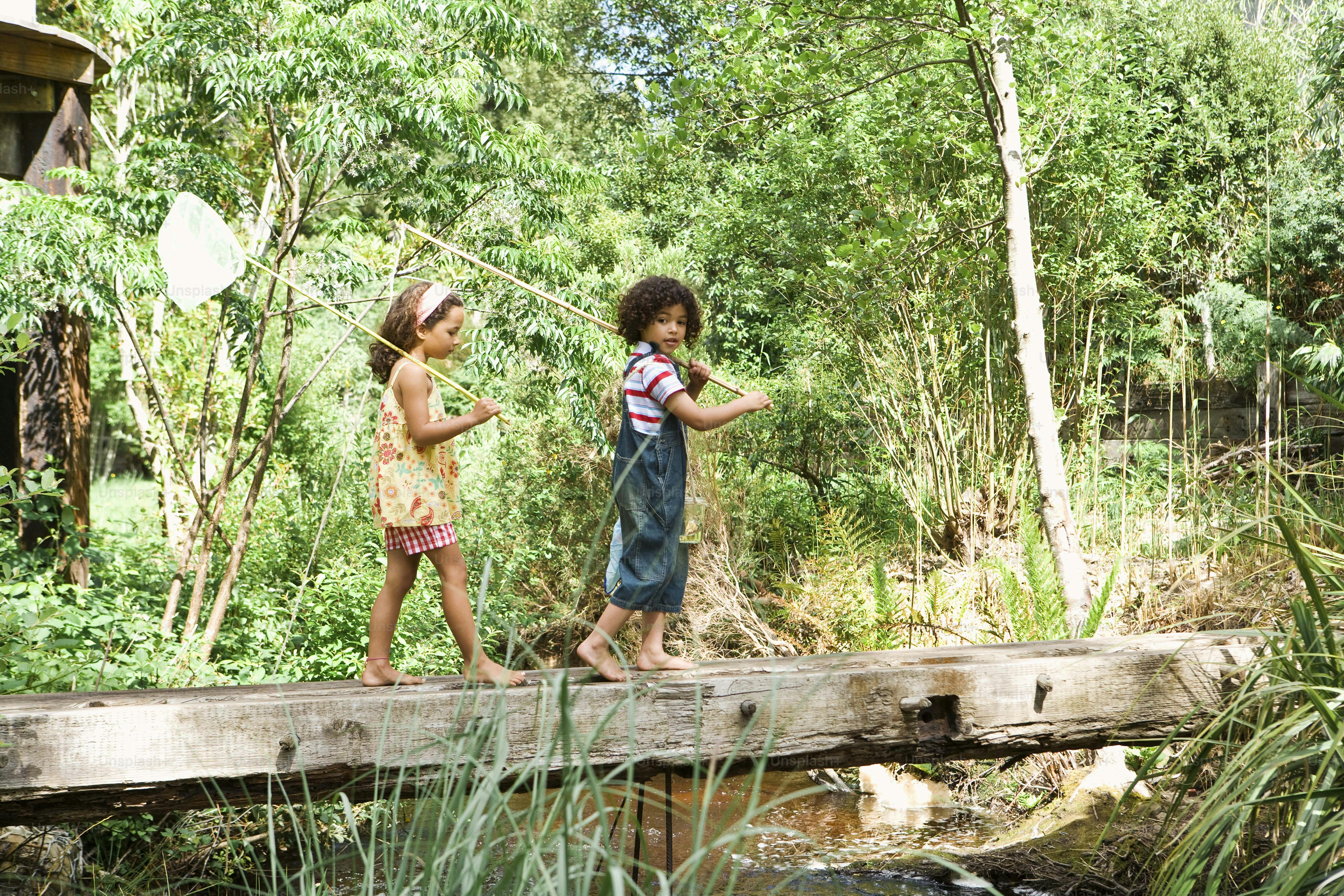 Two little girls walking across a wooden bridge photo – Two people ...