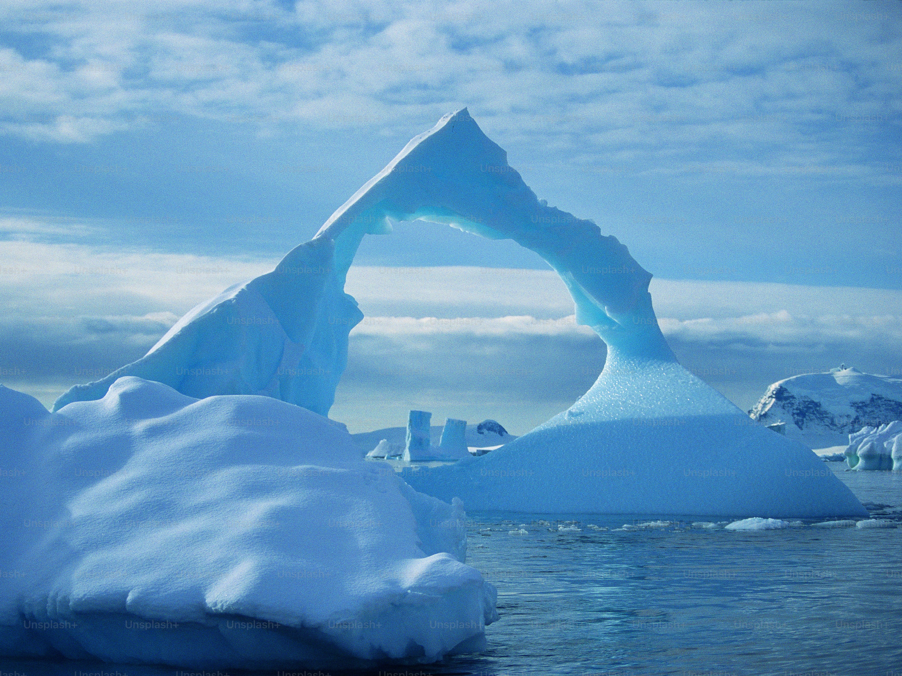 A large iceberg floating in the middle of a body of water photo ...