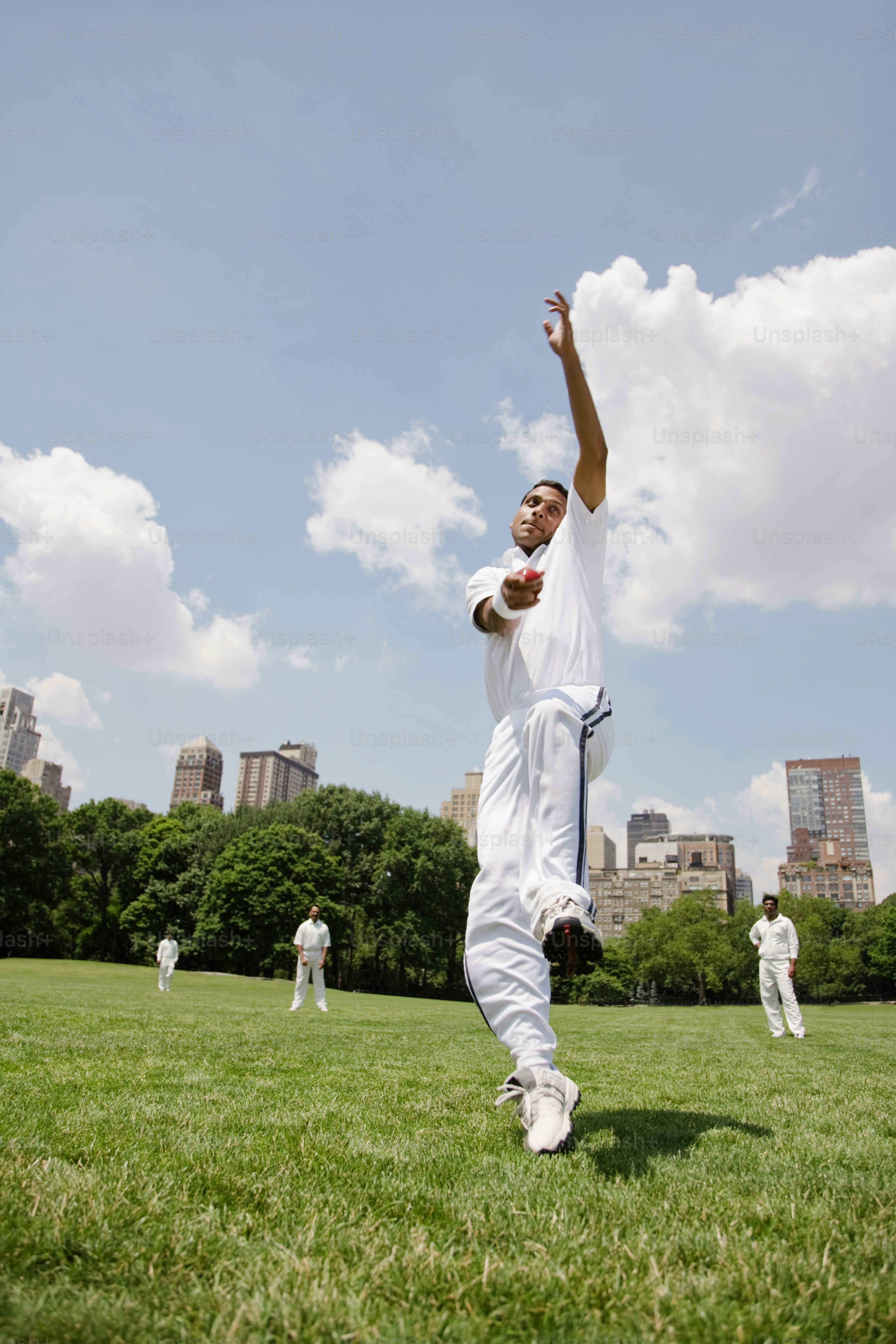 A man in a white uniform is throwing a frisbee photo – Cricket player ...